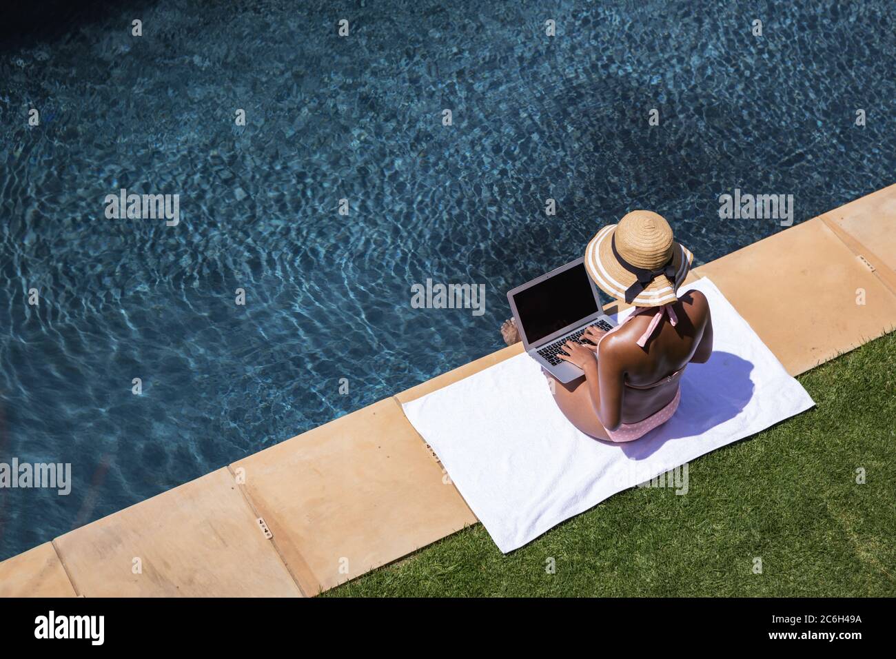 Woman with laptop while sitting by the pool Stock Photo - Alamy