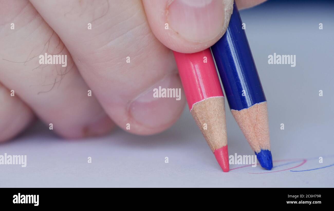 Image with a Person Drawing with Two Colored Pencils on a White Piece ...