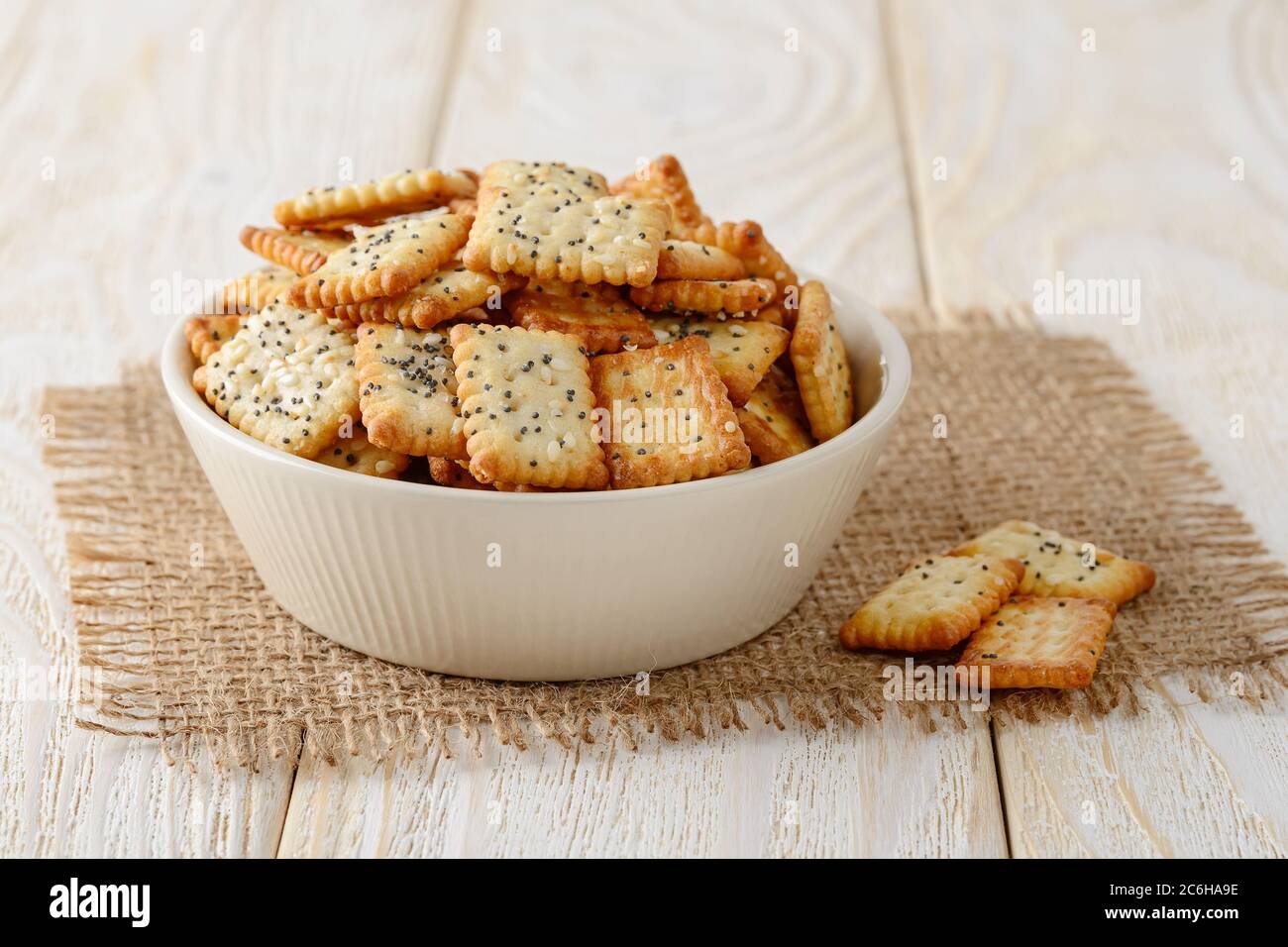 Small salty rectangular crackers with poppy and sesame seeds in a beige ...