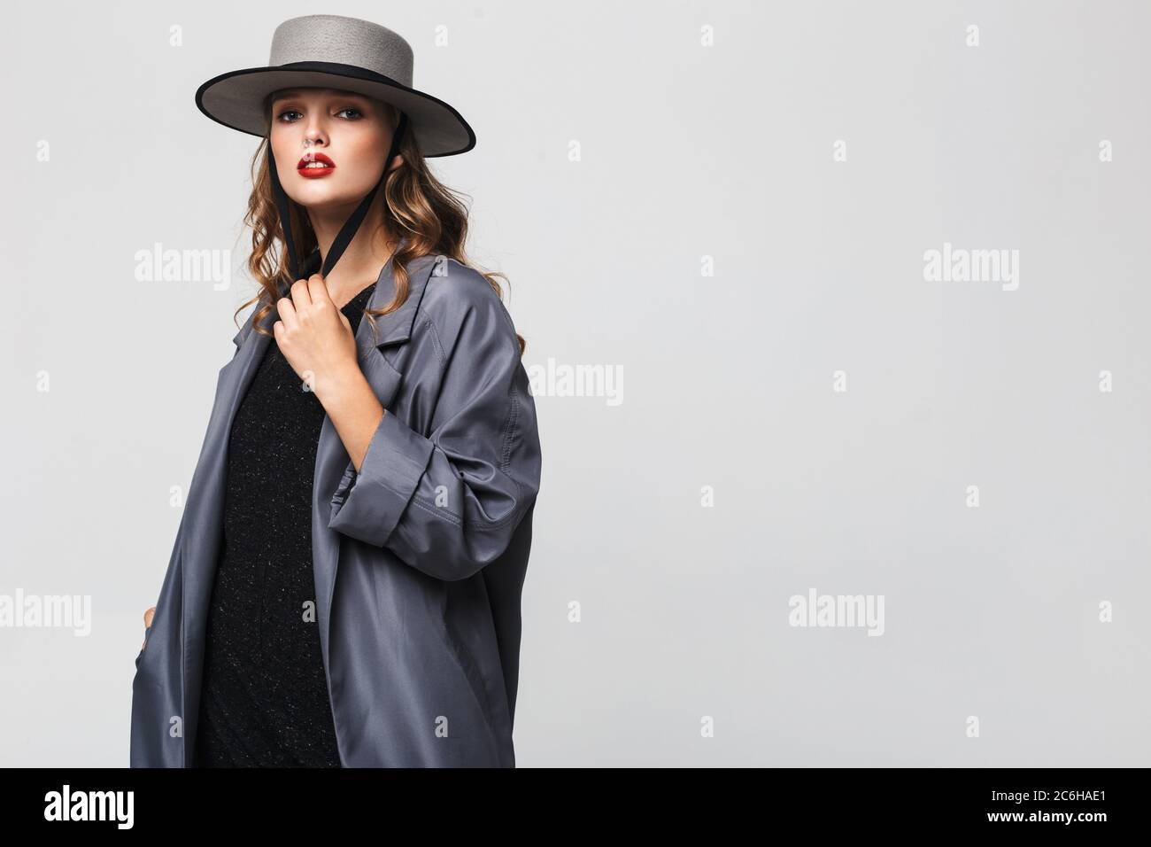 Beautiful pensive girl with wavy hair in hat and cloak dreamily looking ...