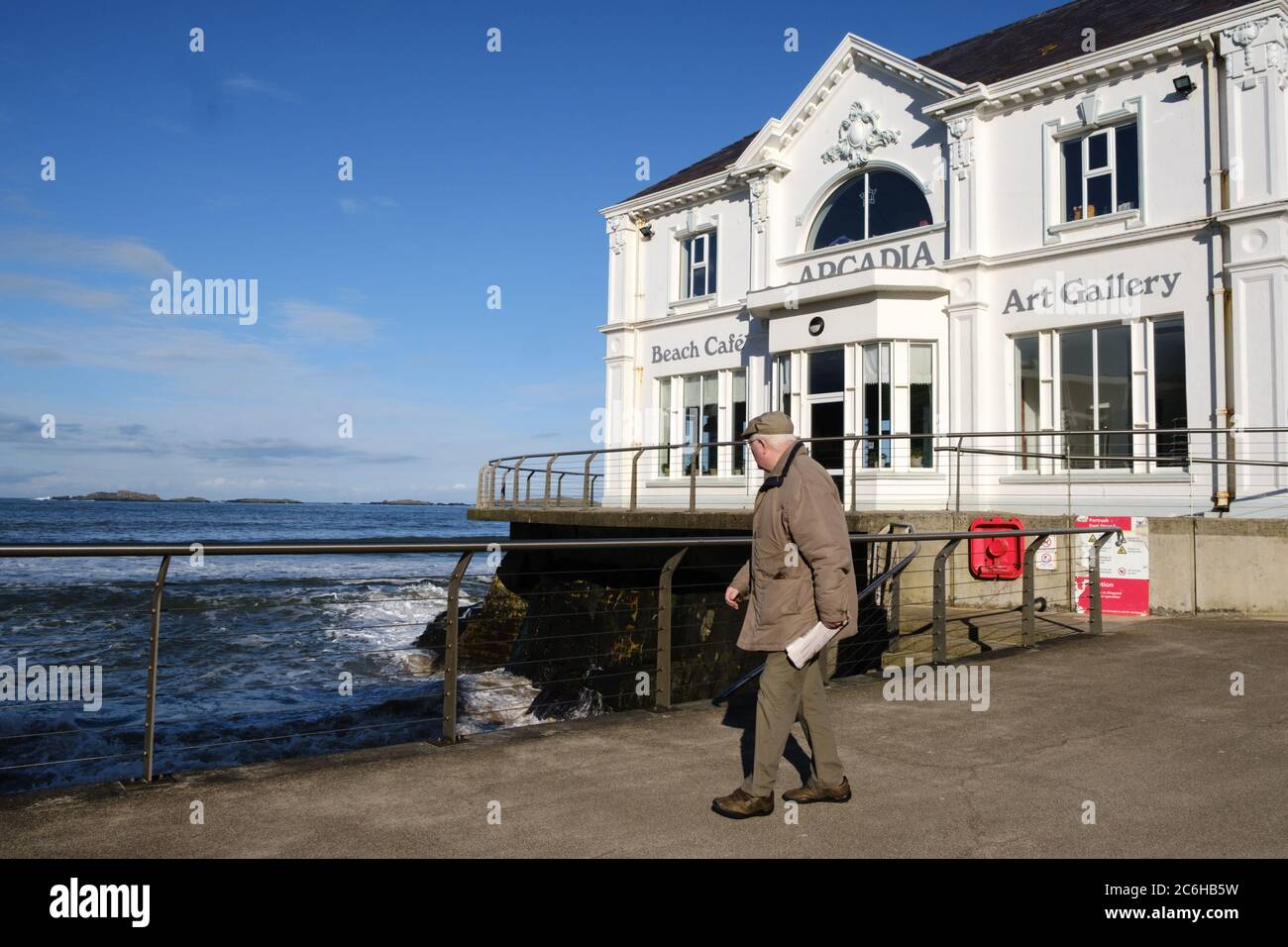 Older gentleman dressed in brown coat and flat cap walks past the ...