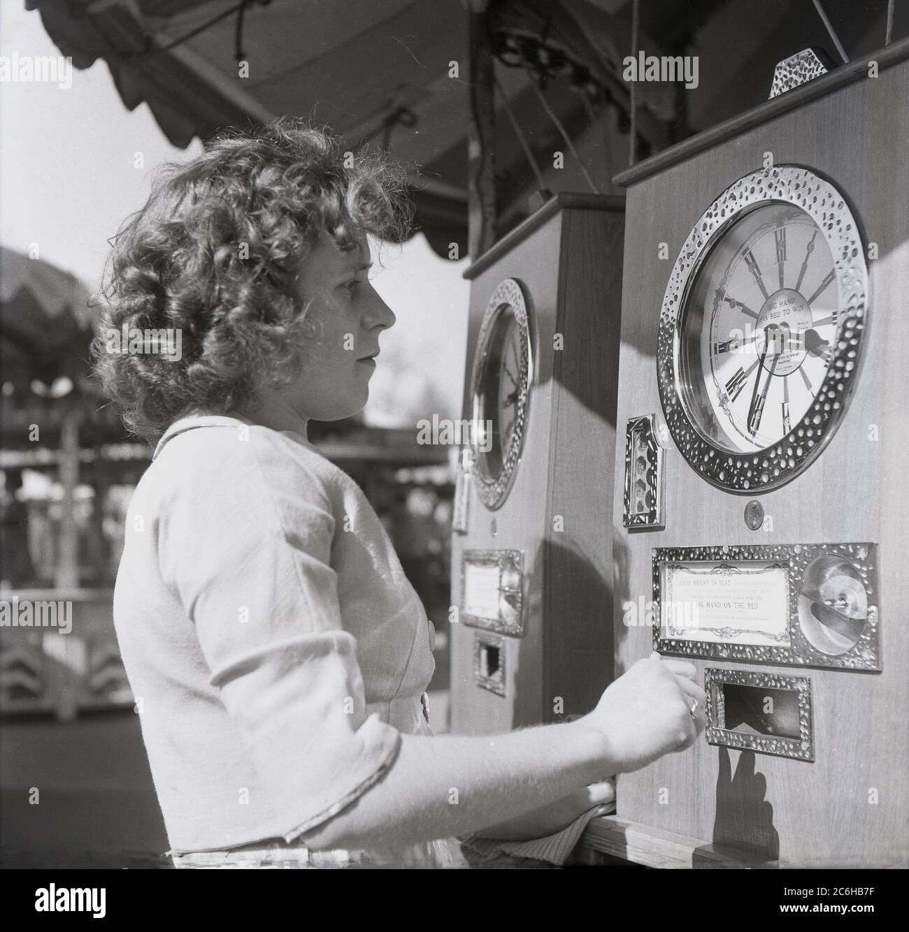 1960s, historical, outside at a funfair, a young women standing playing ...
