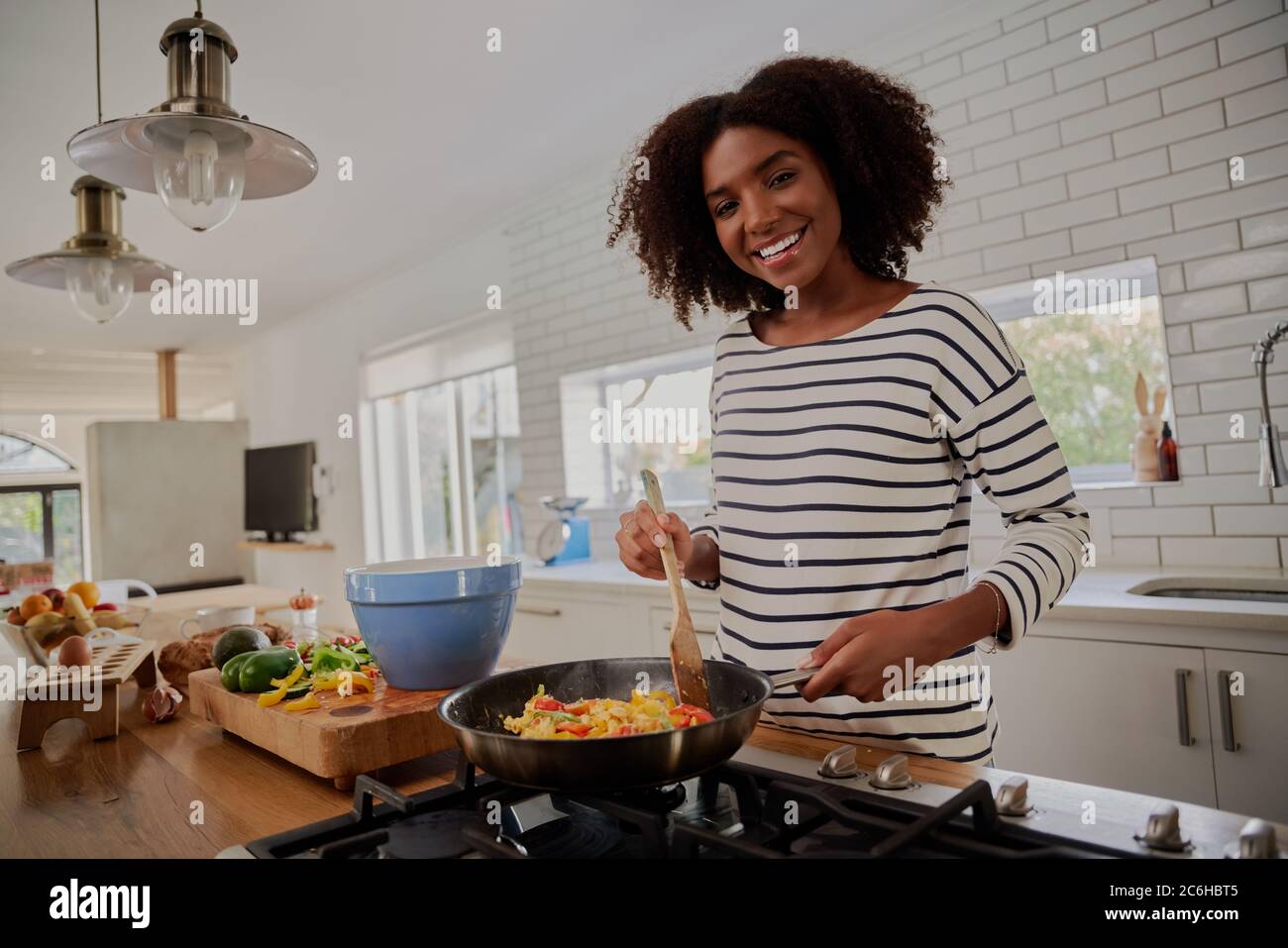 Portrait of young smiling woman mixing ingredients and vegetables in ...