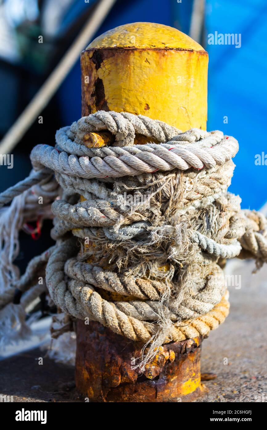 Variety of ropes tied around bright yellow pole securing fishing boats ...