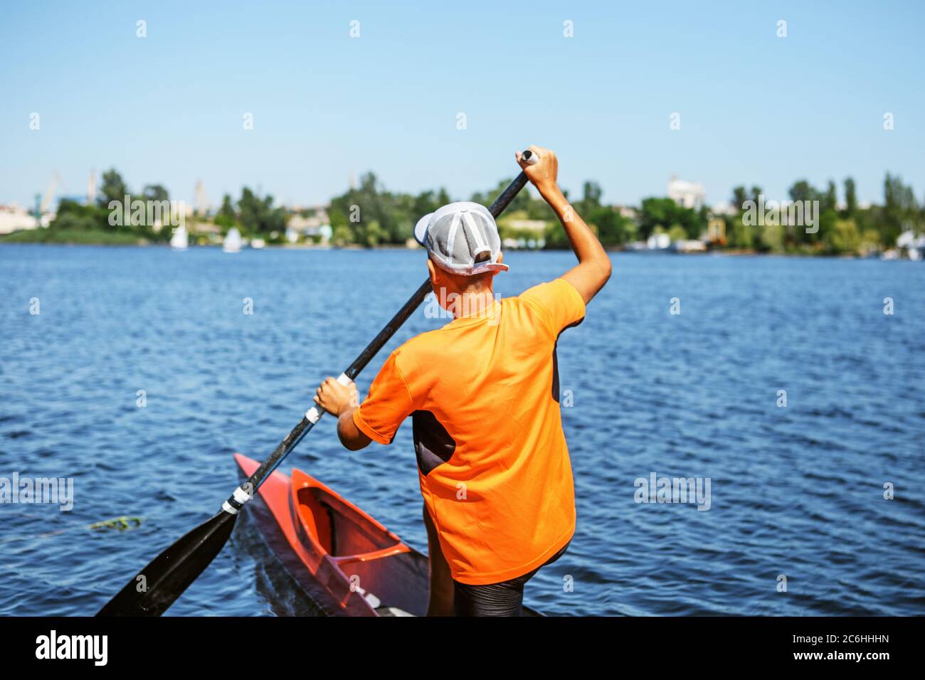 The boy rowing in a canoe on the river. Back view Stock Photo - Alamy