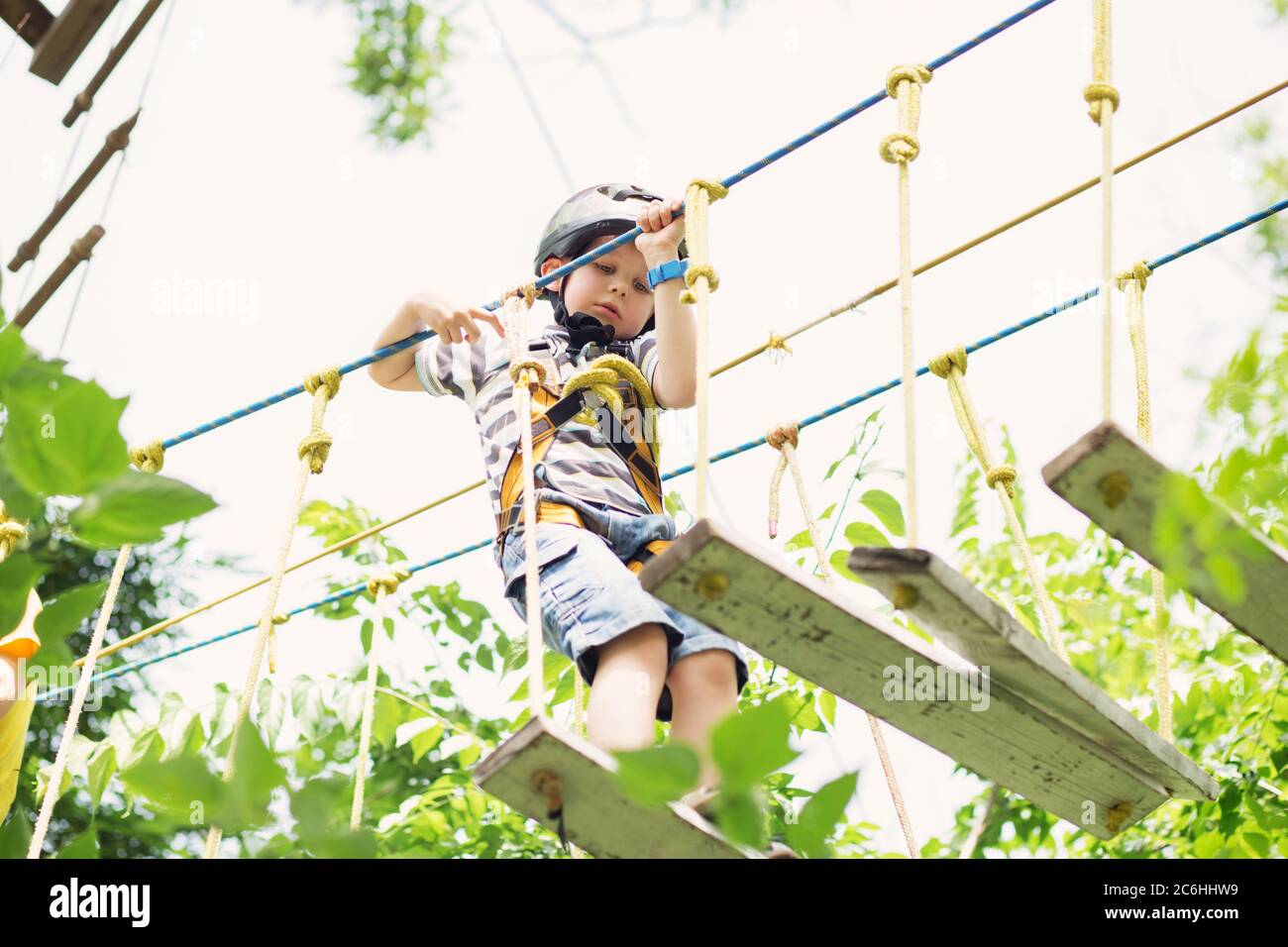 Kids climbing in adventure park. Boy enjoys climbing in the ropes ...