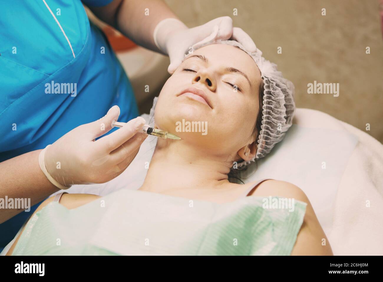 Beautician performs a needle mesotherapy treatment on a woman's face ...