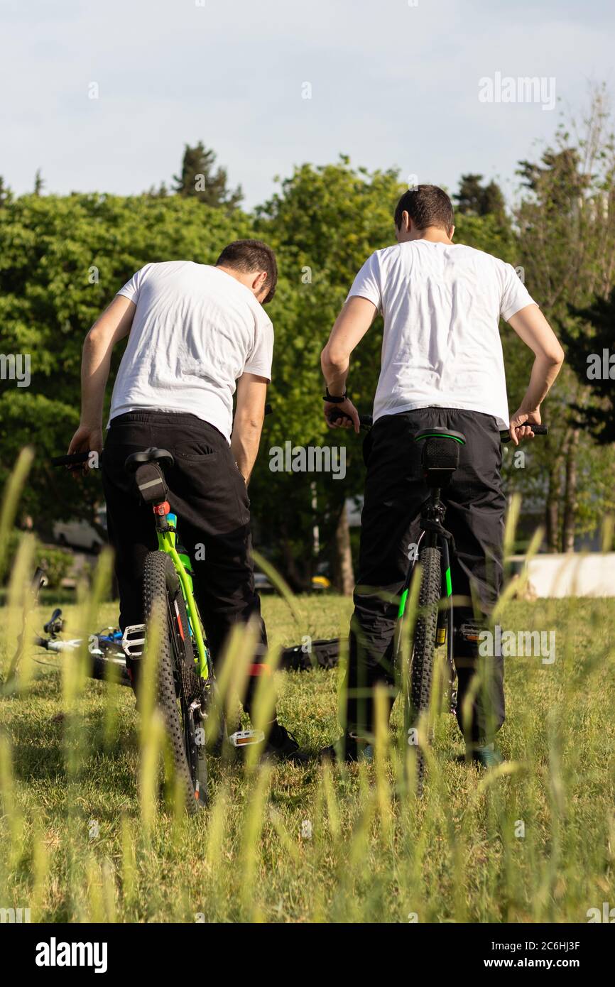 Two friends standing on their green bikes in a park, talking and ...