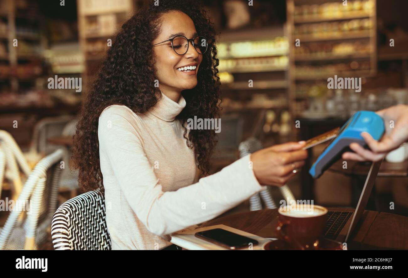 Smiling woman paying contactless using her credit card in a cafe to pay ...