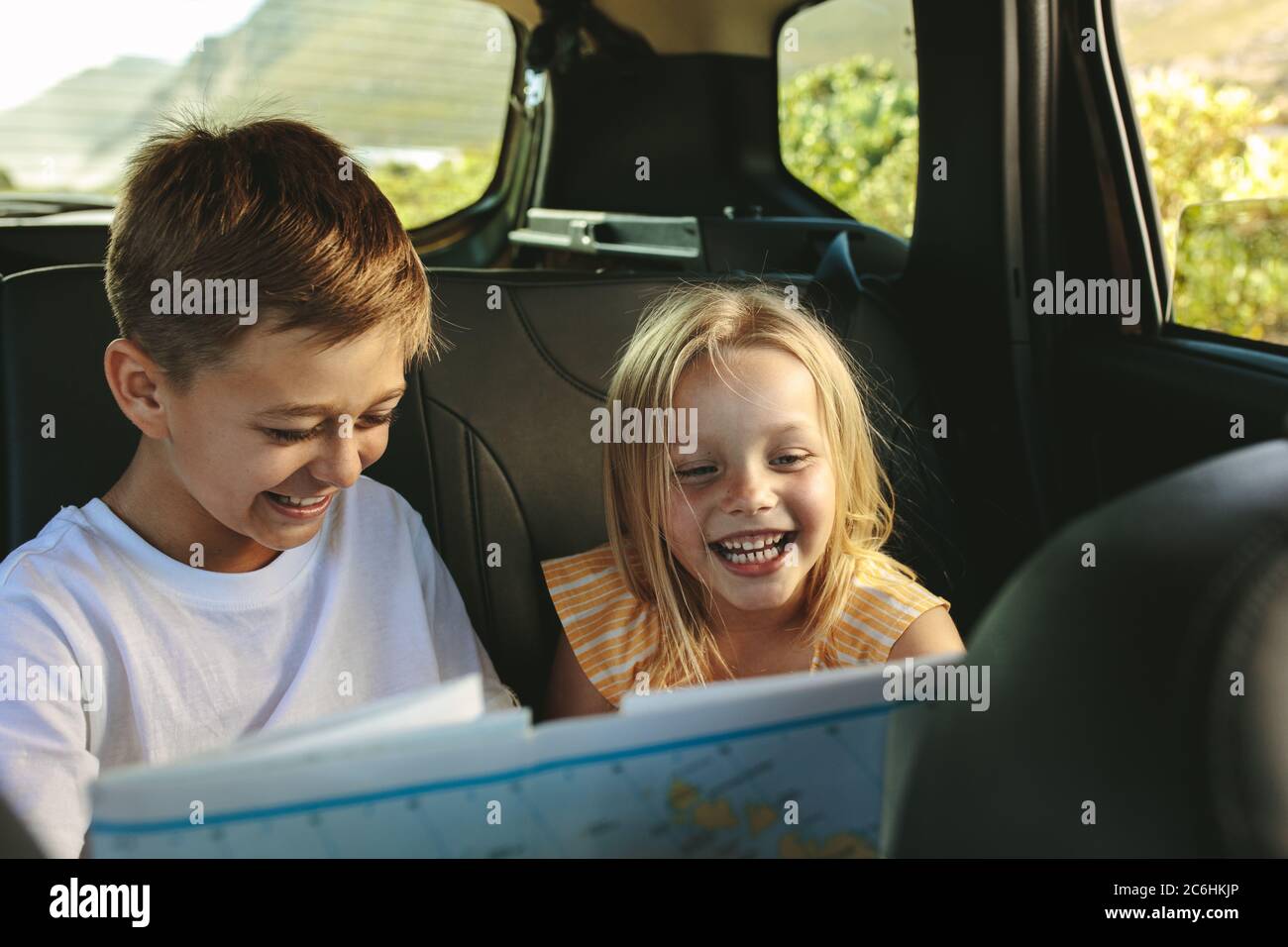 Two kids exploring a map while travel by car. Children going on ...