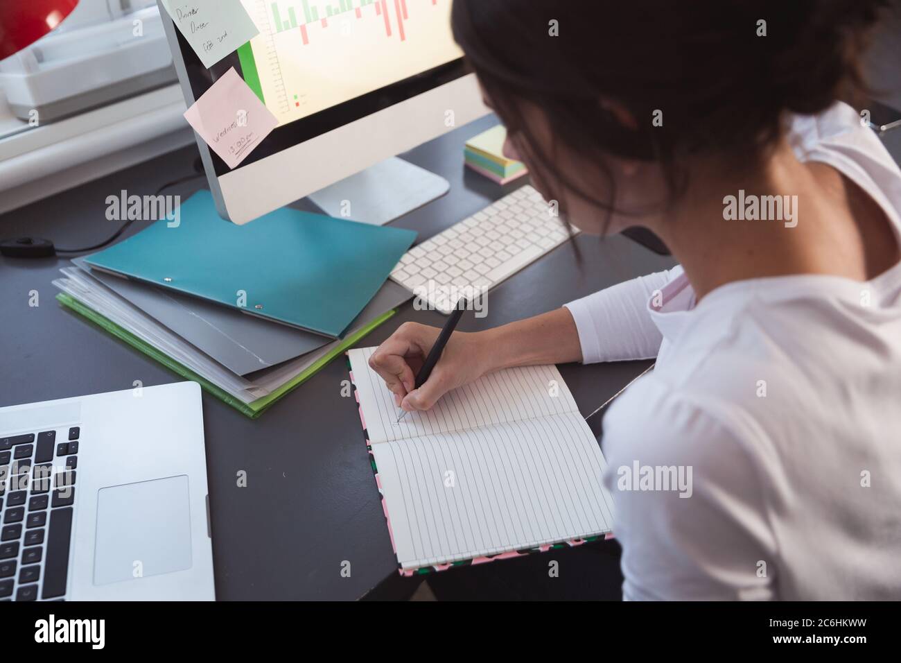 Woman taking notes while sitting on her desk Stock Photo - Alamy