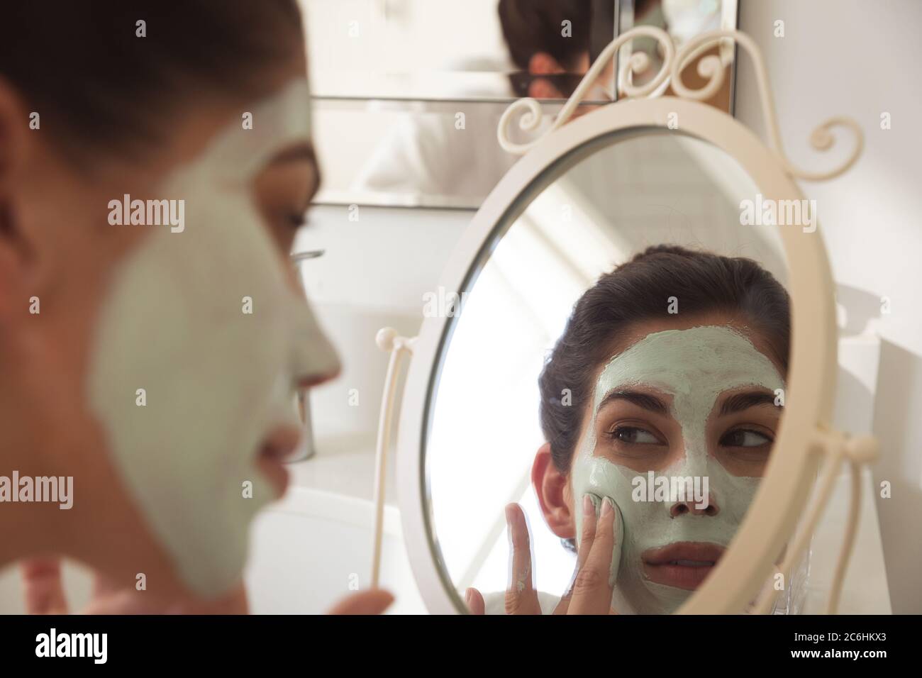 Woman applying facial mask while look in the mirror Stock Photo - Alamy