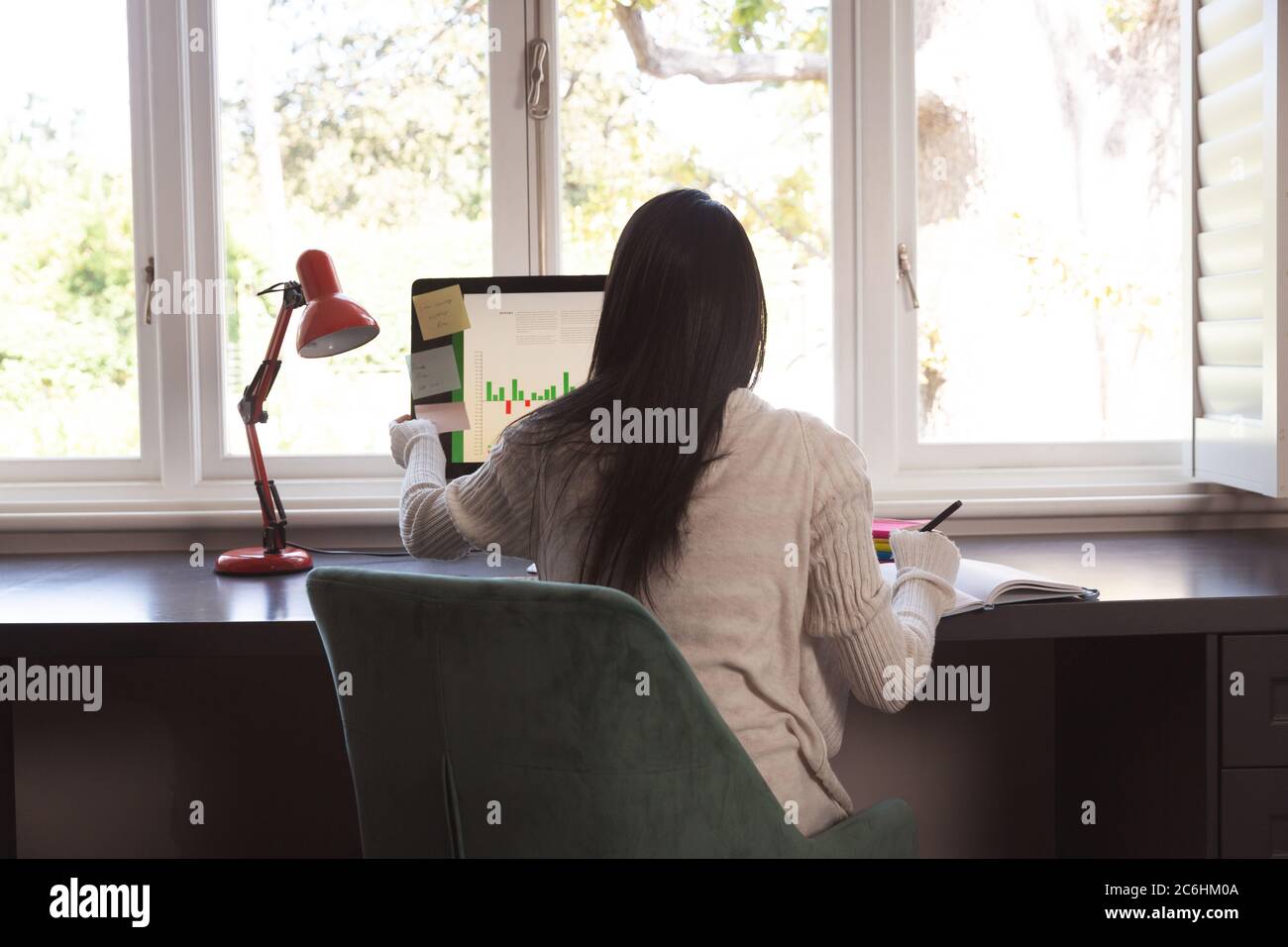 Woman using computer while sitting on her desk Stock Photo - Alamy