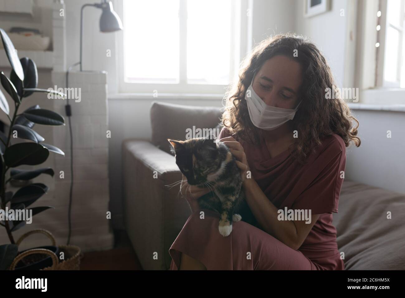 Woman wearing face mask holding her cat at home Stock Photo - Alamy
