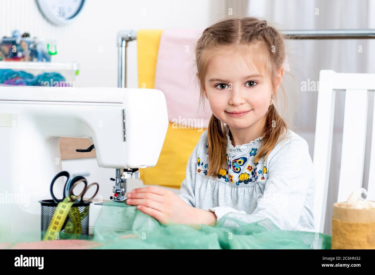 Little girl using sewing machine to make crafts in the workshop and ...