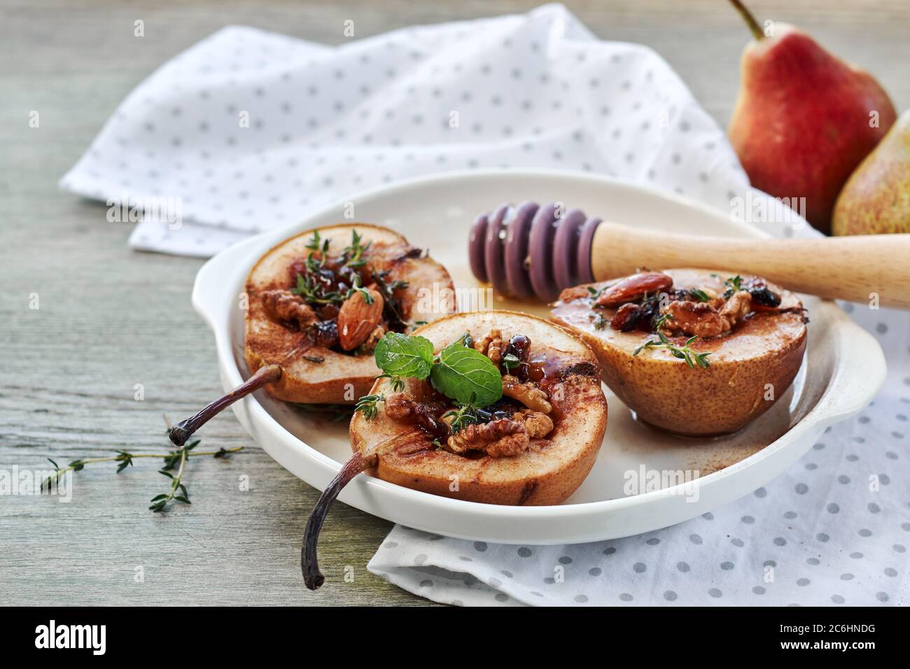 Baked pears with nuts, raisins, honey and cinnamon in a white plate on ...