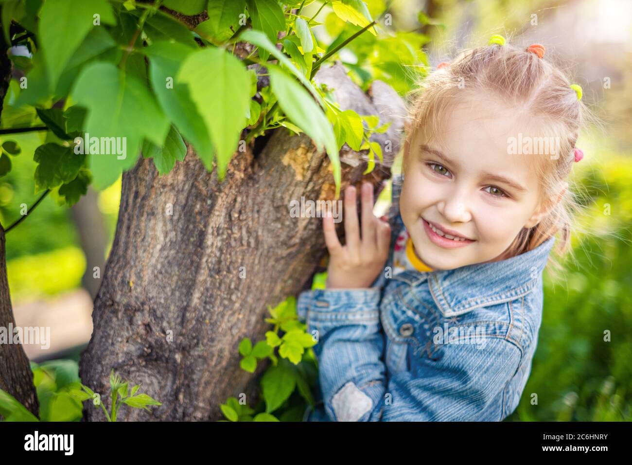 Little girl playing behind a tree hi-res stock photography and images ...