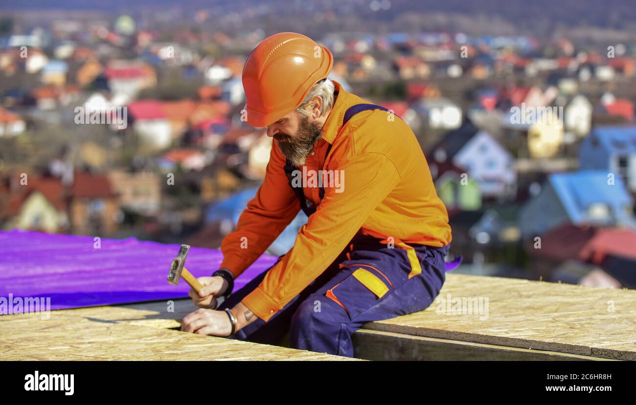 Roofer worker in special protective work wear. new roof under ...