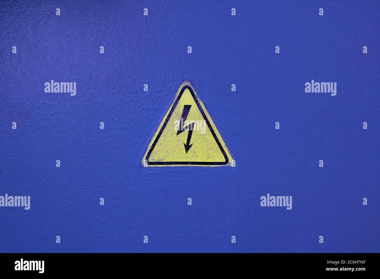 Yellow electricity sign on a blue wall Stock Photo - Alamy
