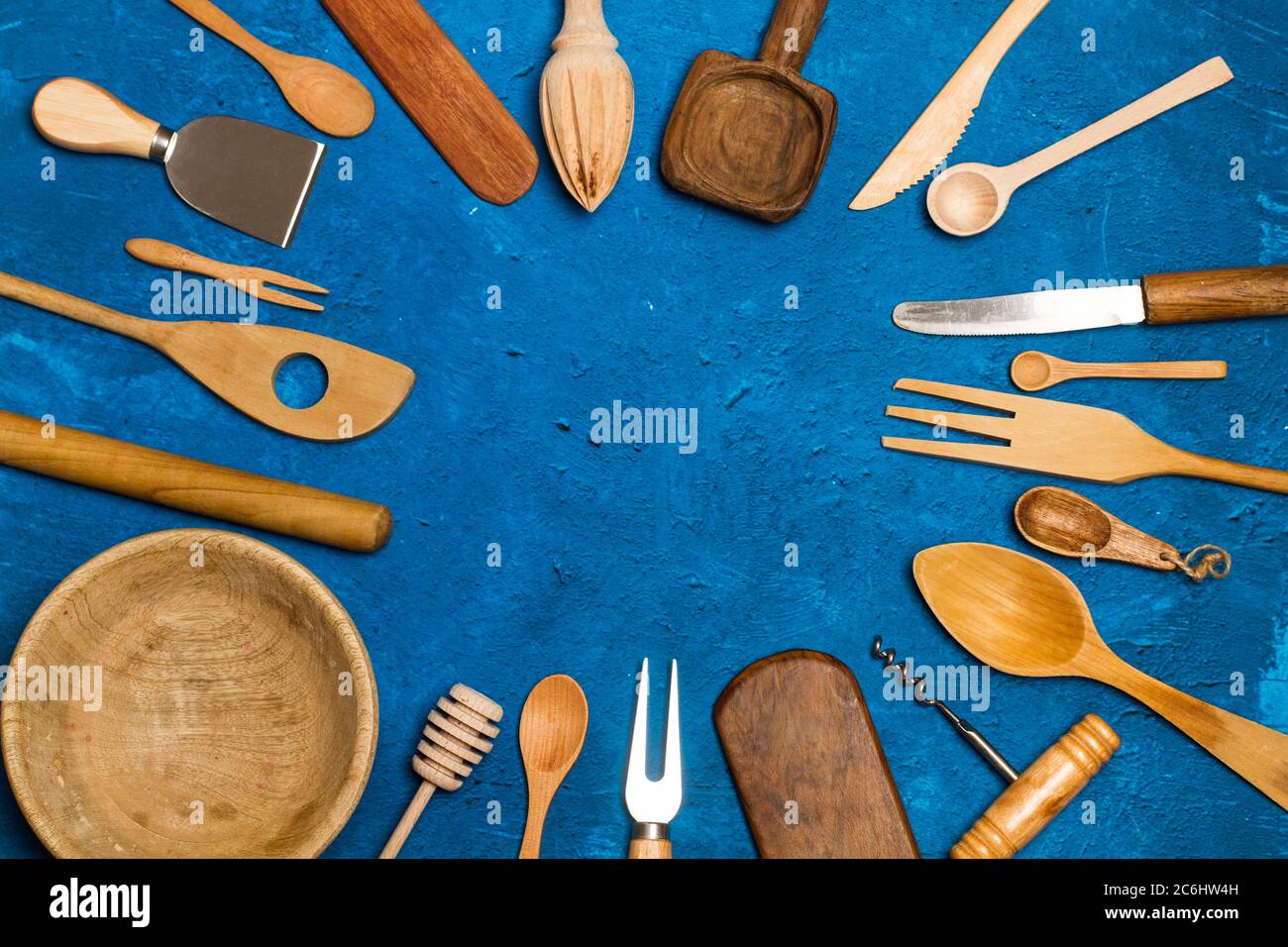 Assorted wooden kitchenware on a textured classic blue background in a ...