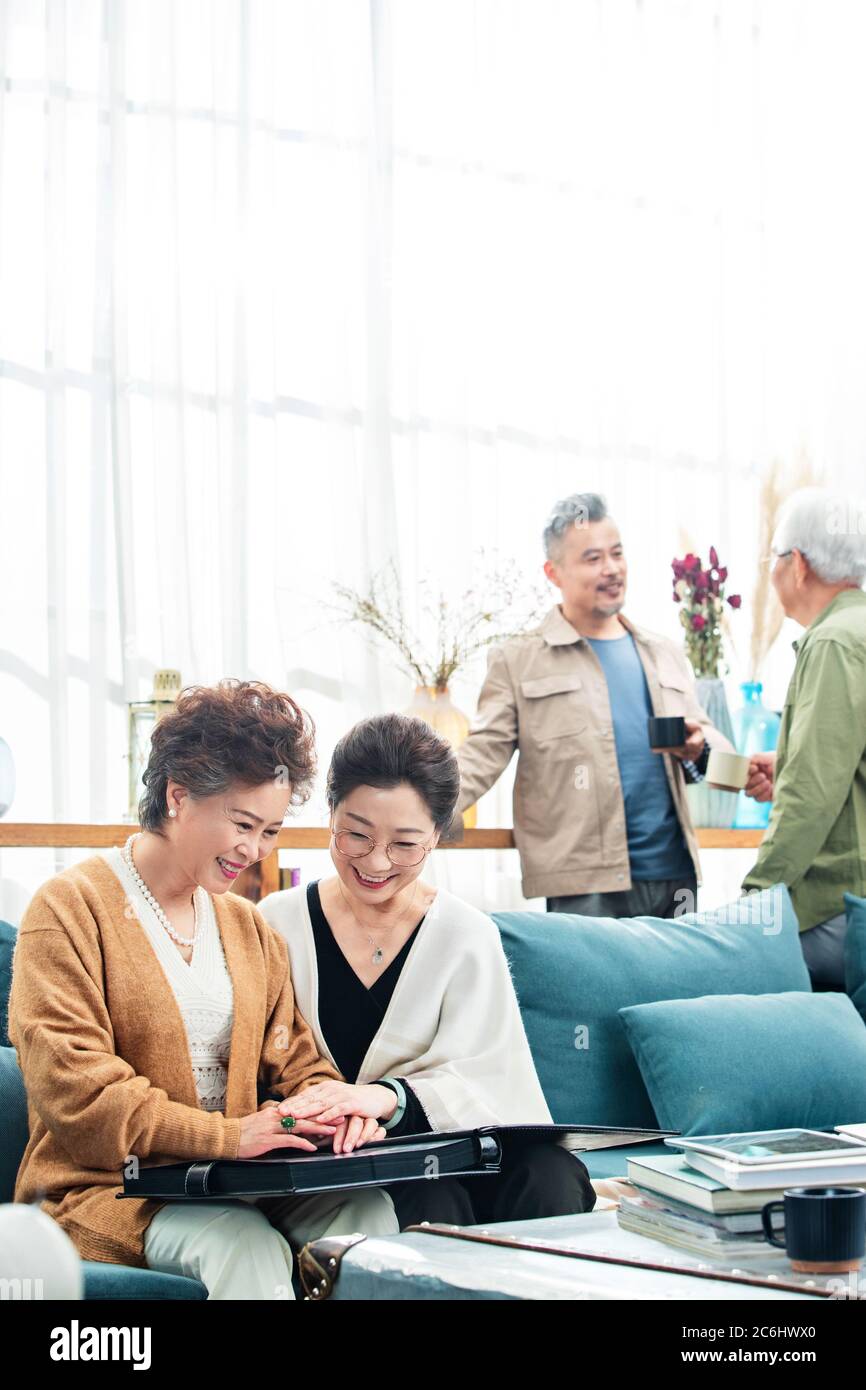 Happy middle-aged and old people drink tea chat to see photo album ...