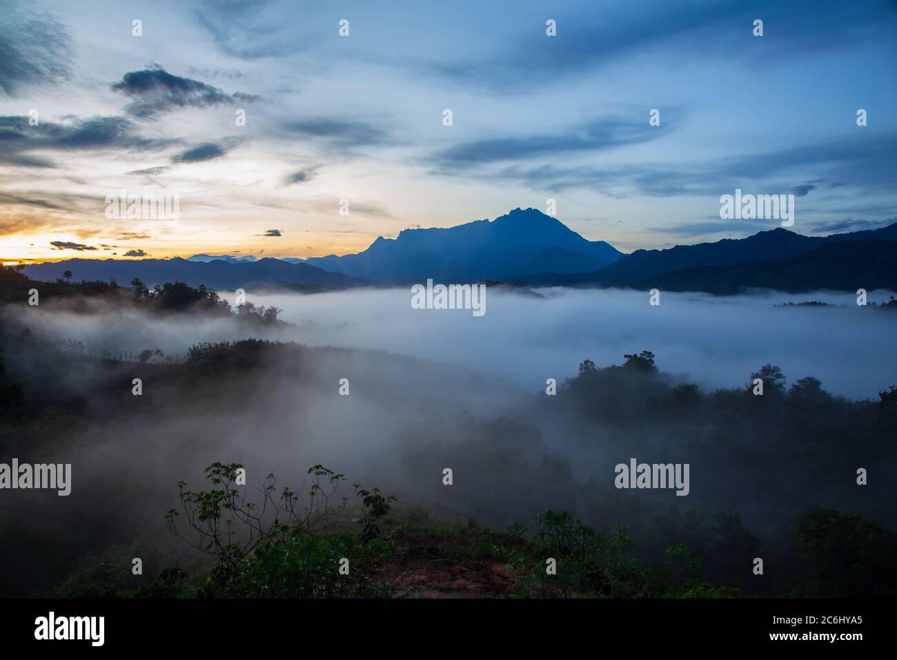 Beautiful landscape scenery with sunlight and fog and Mount Kinabalu as ...