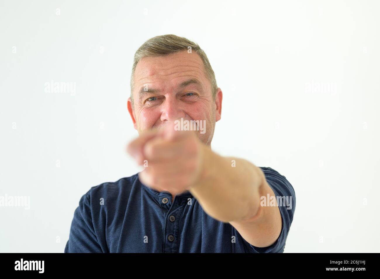 Cheerful smiling man pointing ahead at the camera with focus over his ...