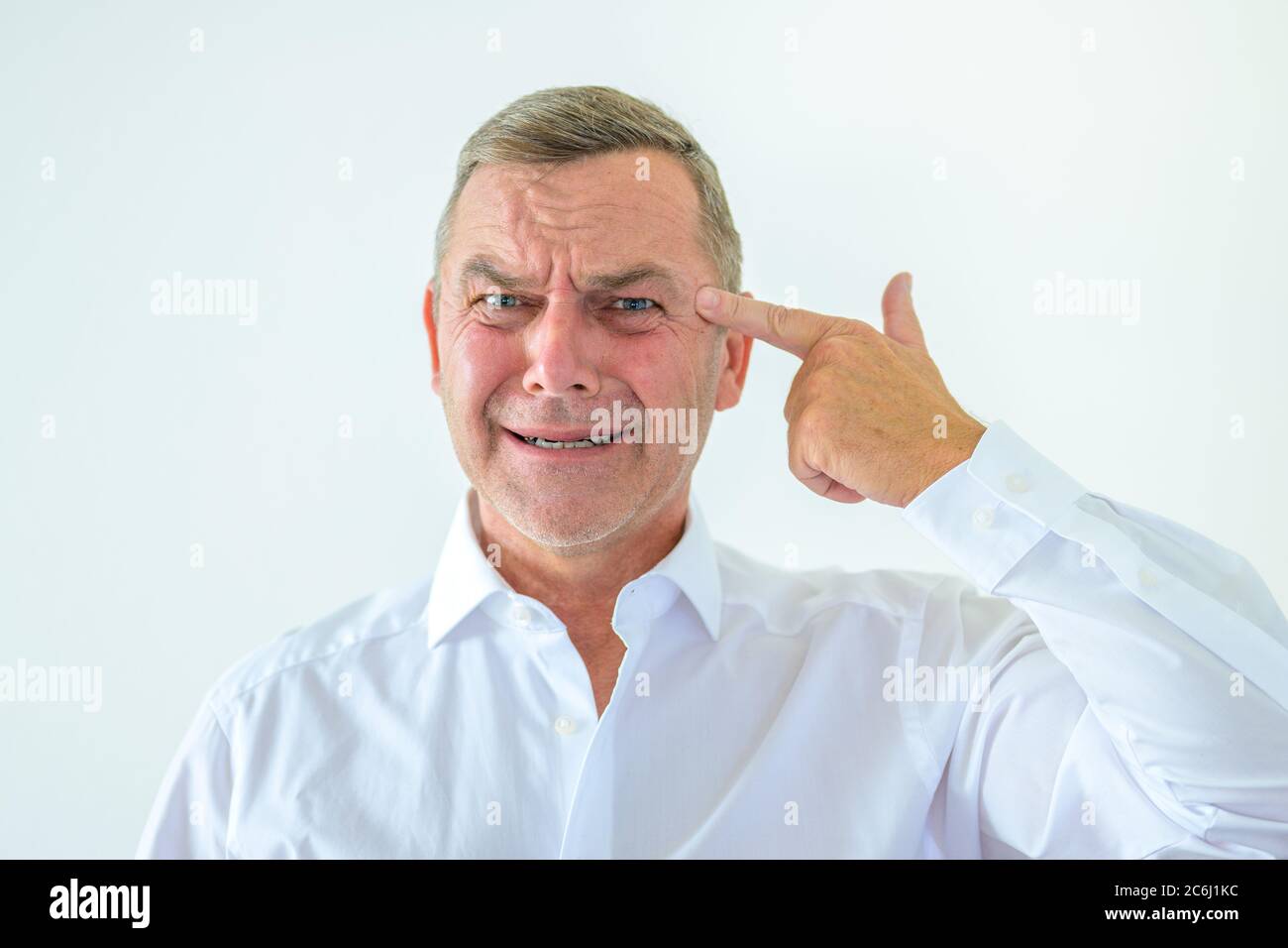 Man making a gun gesture with his hand pointing to his forehead with an ...