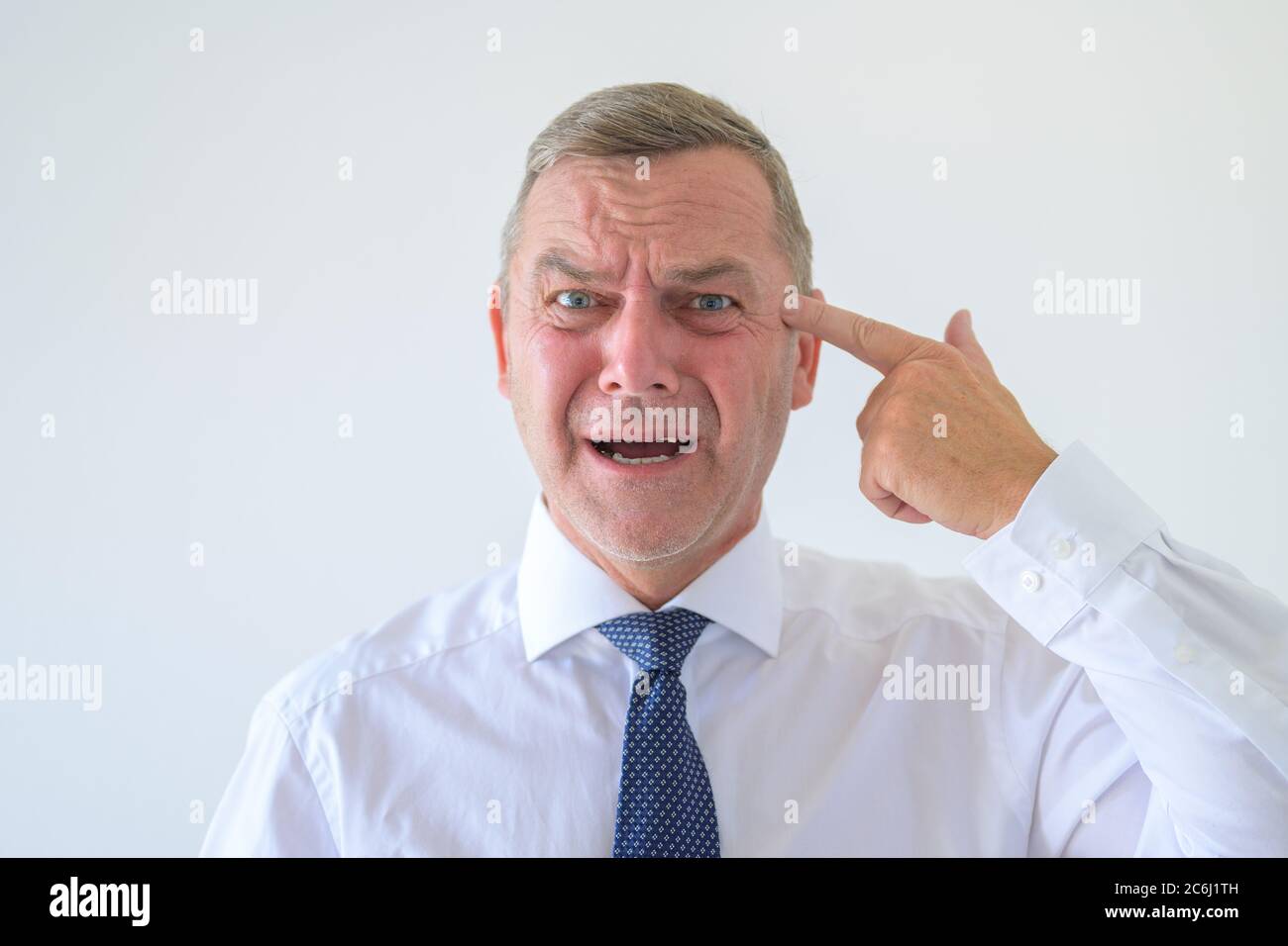Worried man with an anguished hopeless expression making a gun gesture ...