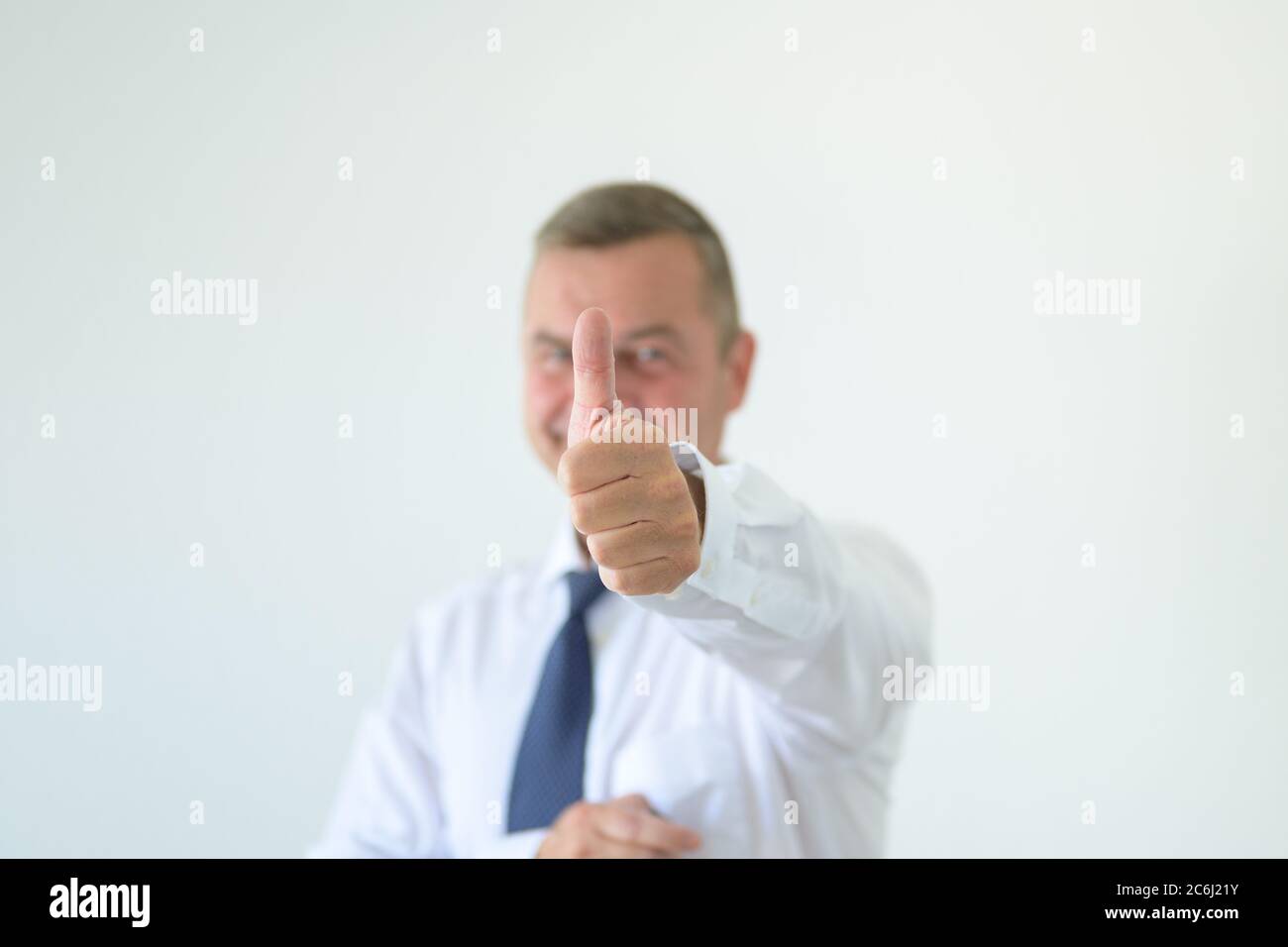 Successful businessman making a thumbs up gesture with focus to the ...