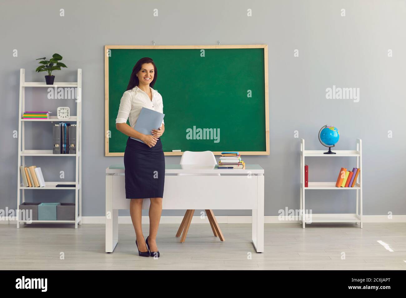 Teacher with a book in his hand standing in class Stock Photo - Alamy