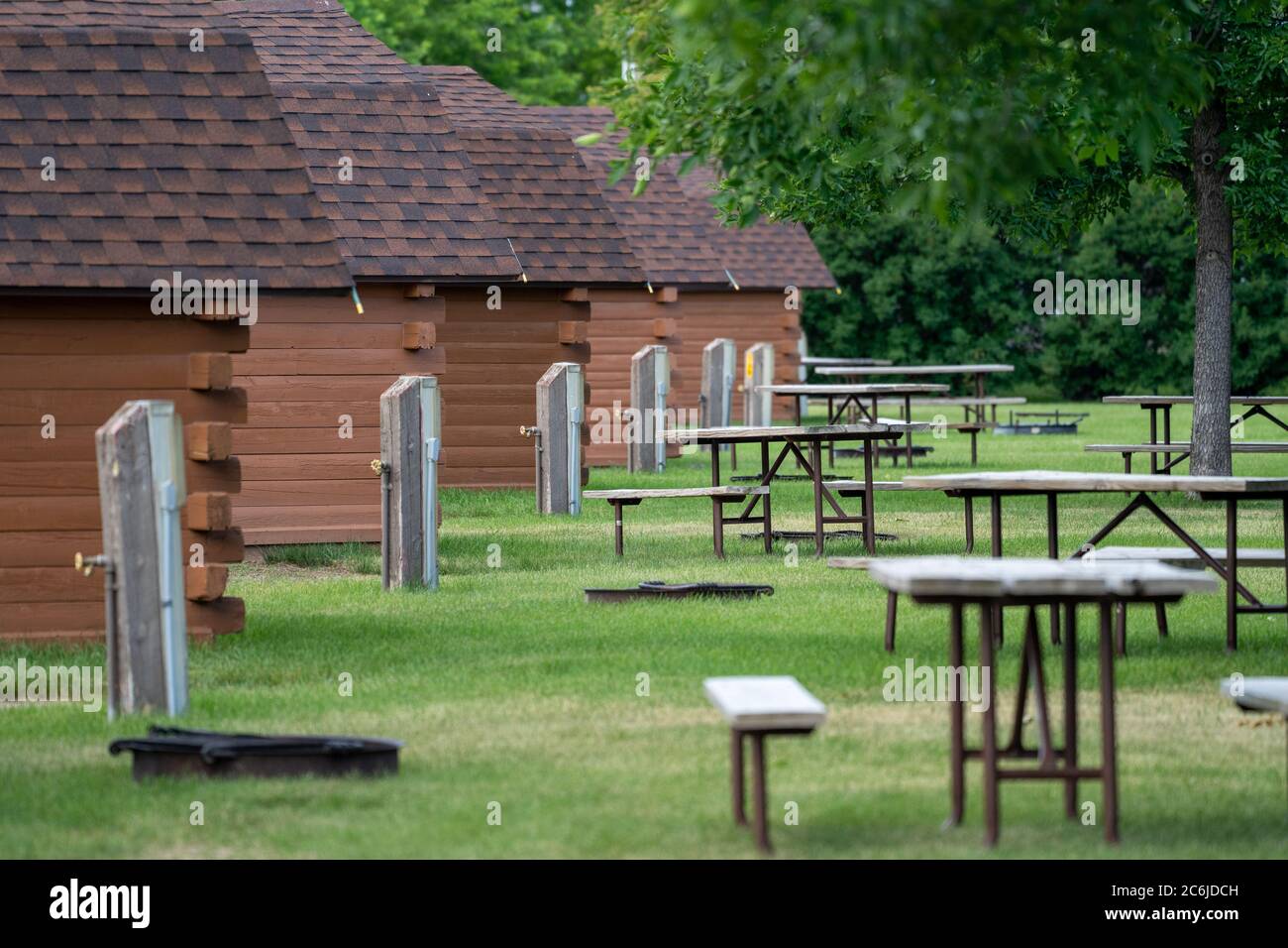 Rows of rustic camping cabins, with water pumps and picnic tables at a ...