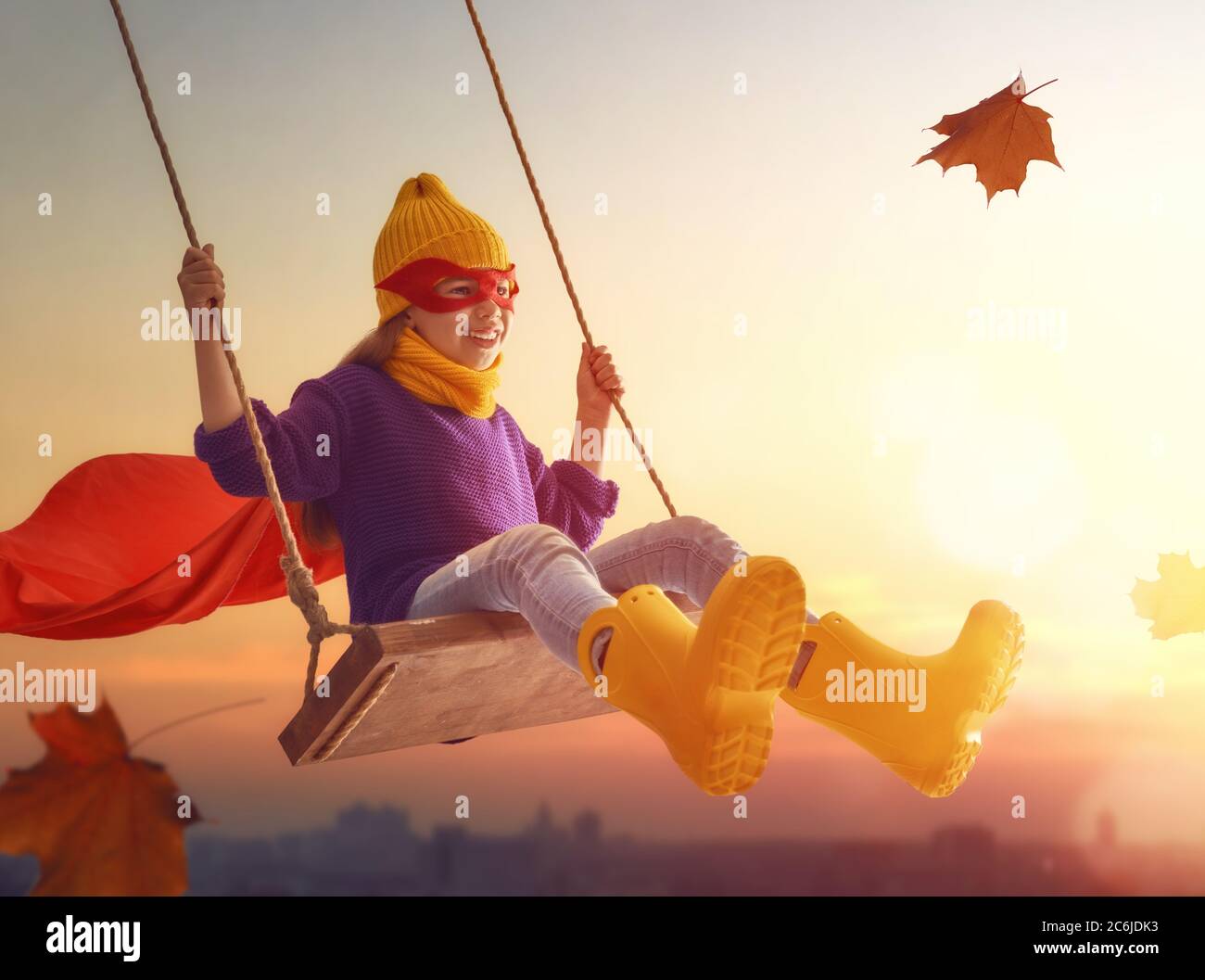 Happy child on swing in sunset fall. Little kid playing in the autumn ...