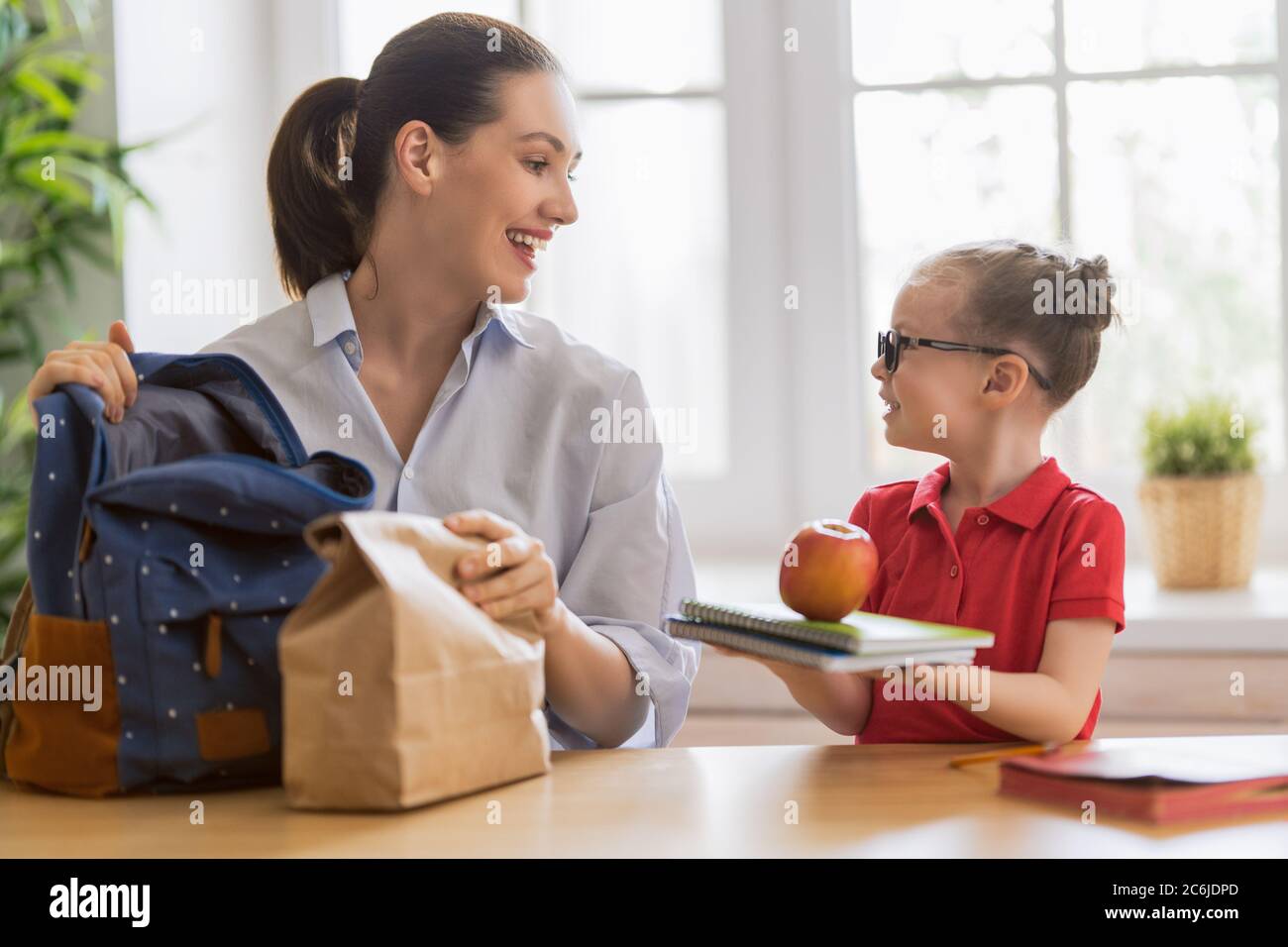 Happy family preparing for school. Little girl with mother putting ...