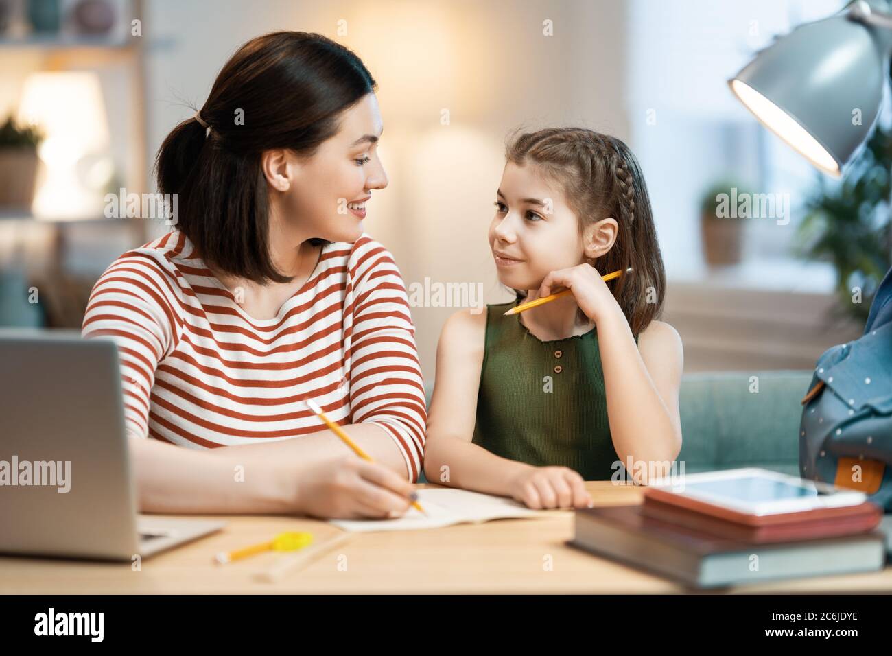 Back to school. Happy child and adult are sitting at desk. Girl doing ...