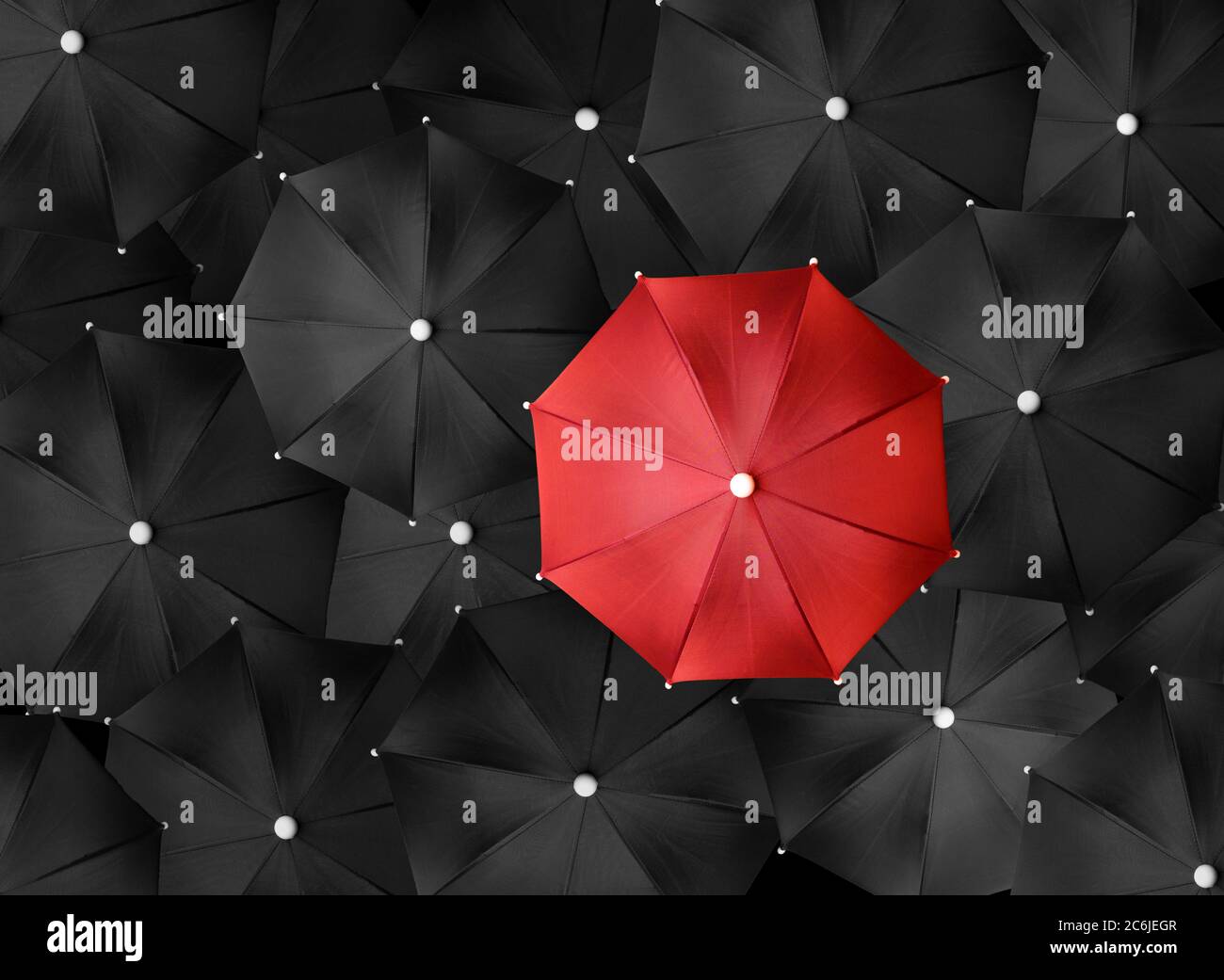Concept image with lots of black umbrellas and a red umbrella that ...