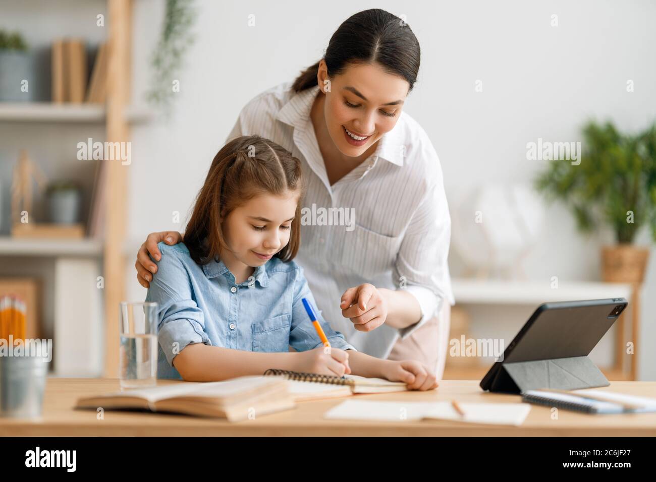 Back to school. Happy child and adult are sitting at desk. Girl doing ...