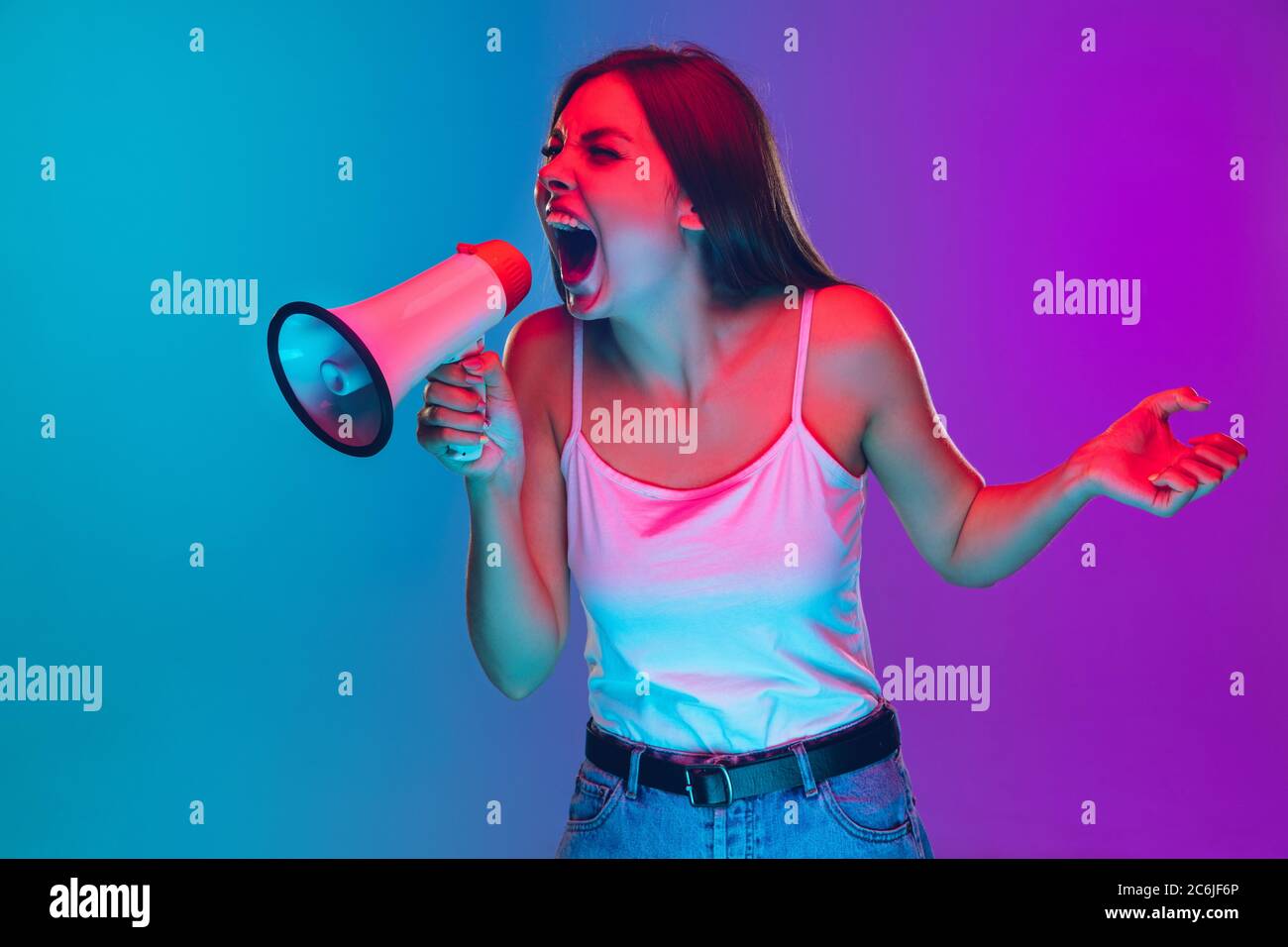 Shouting with megaphone. Caucasian young woman's portrait on gradient ...