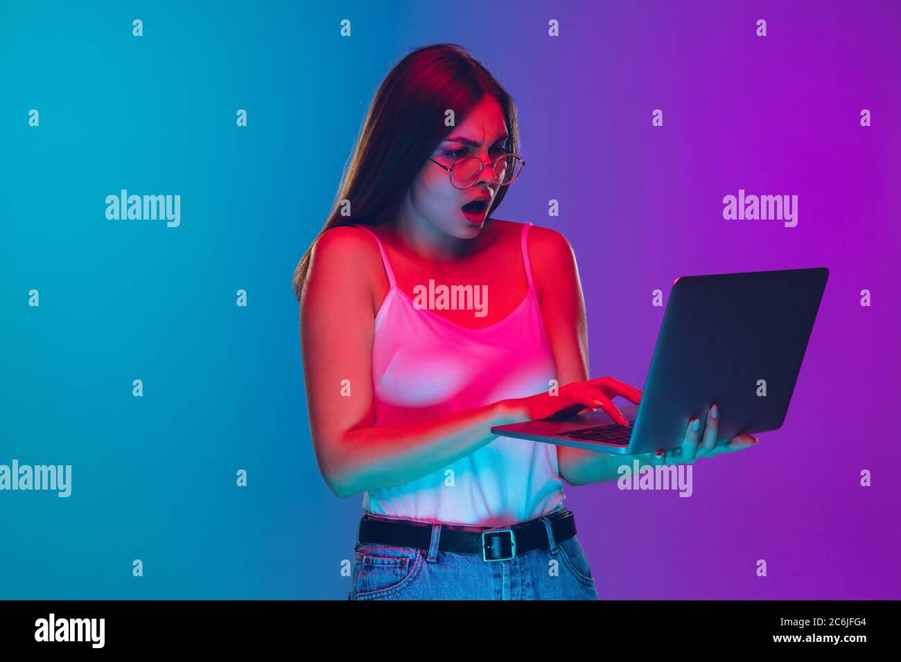 Shocked. Typing, using laptop. Caucasian young woman's portrait on ...