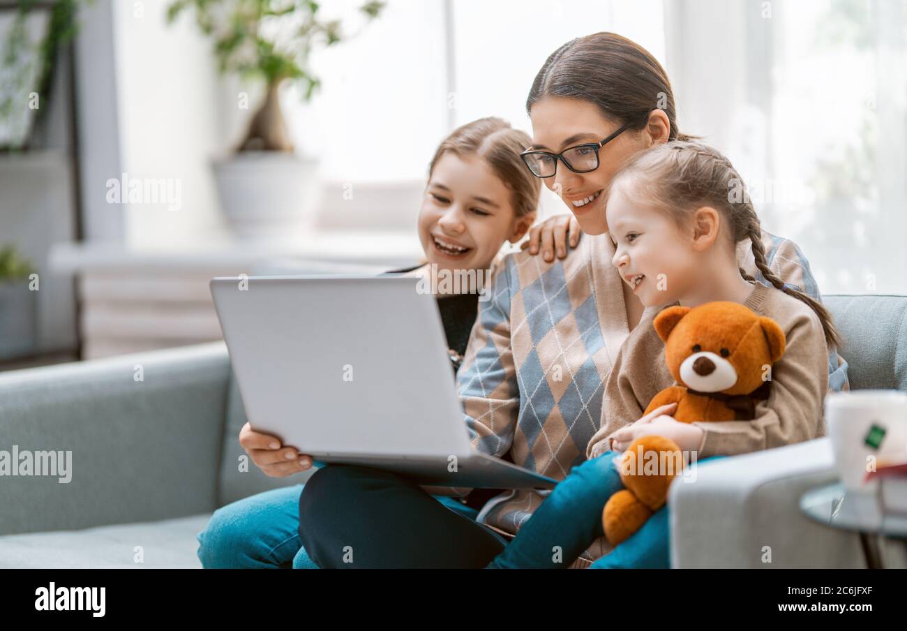 Happy loving family. Young mother and daughters girls using laptop ...