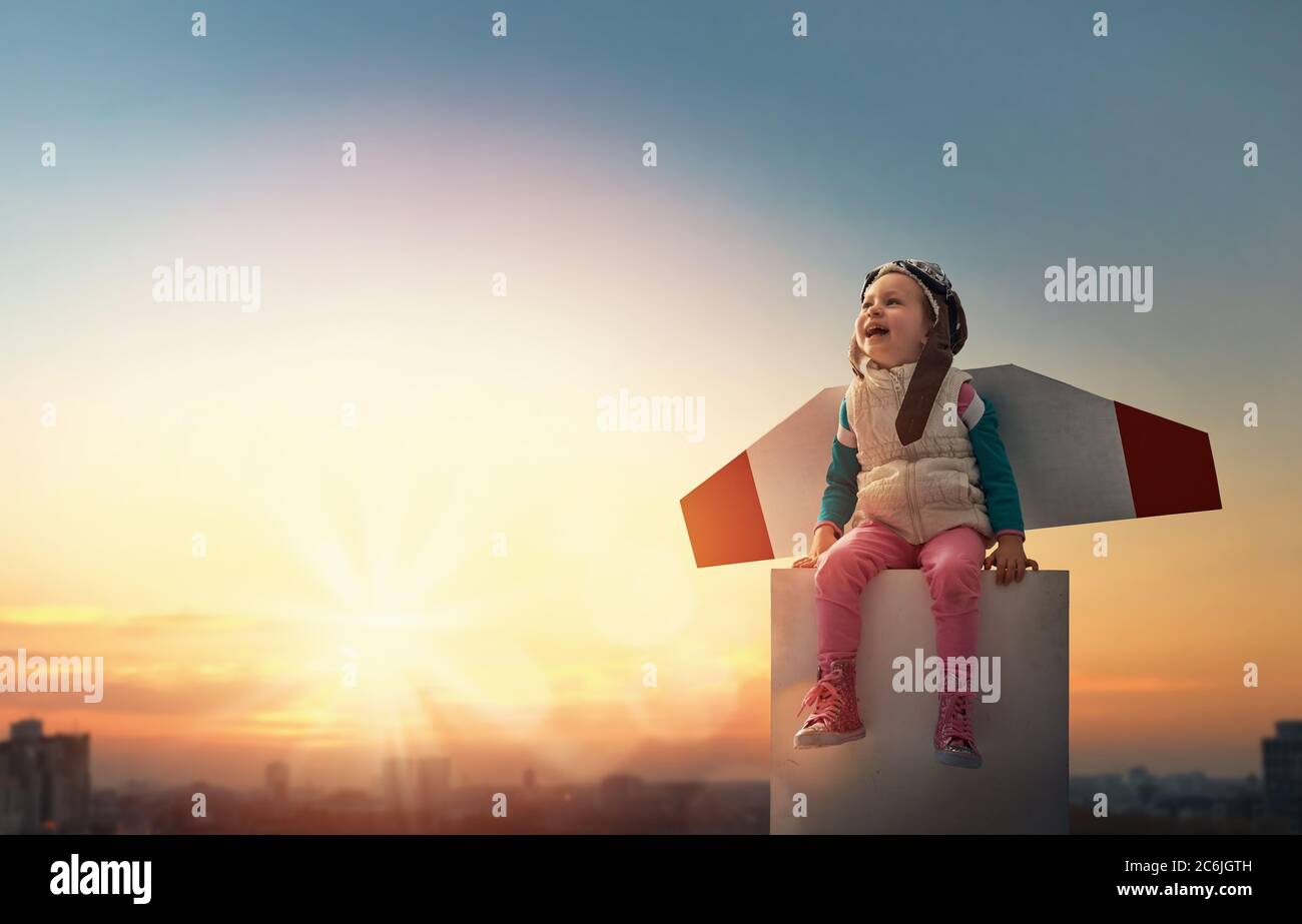 Little child playing pilot. Girl on the background of sunset sky. Kid ...