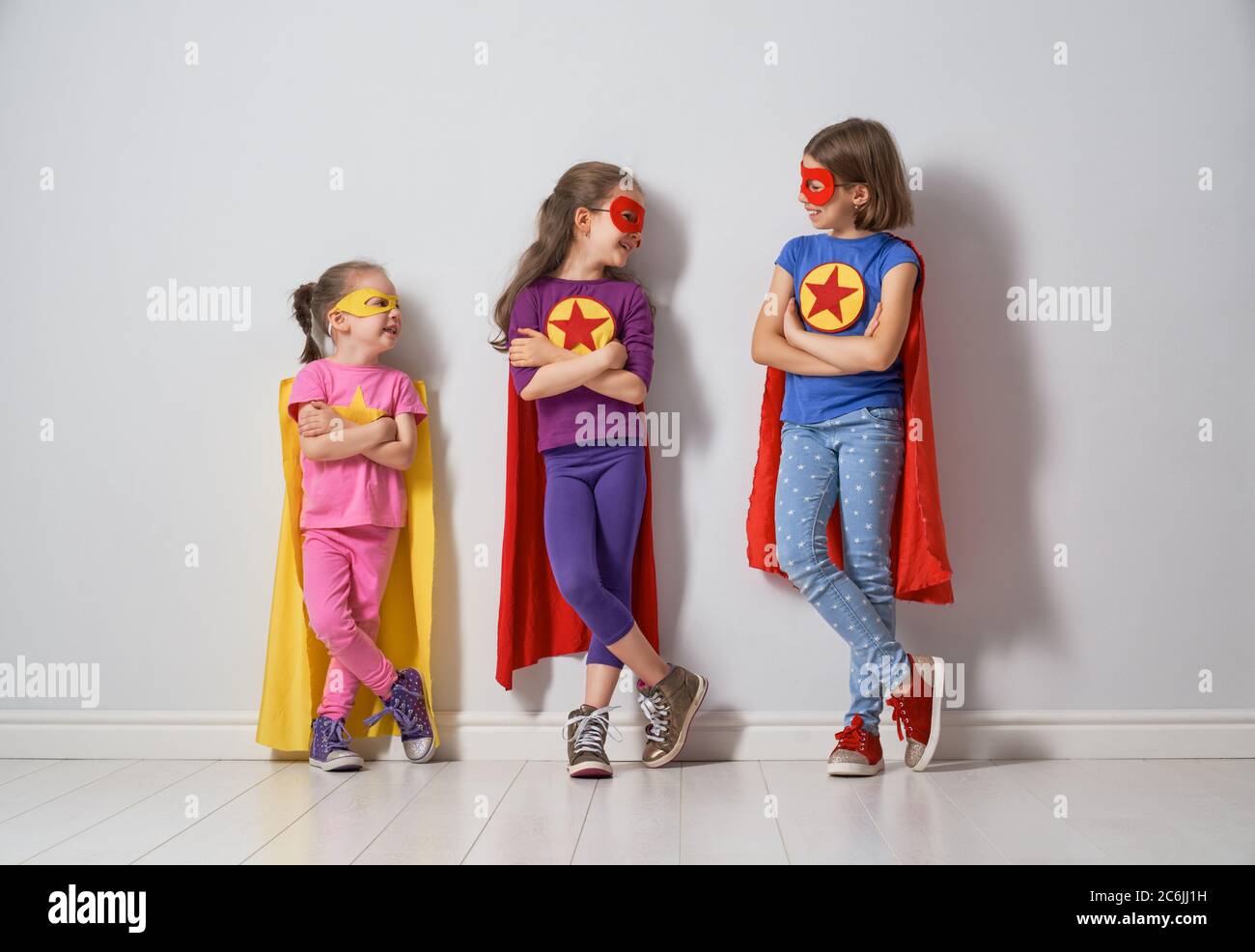 Little children are playing superhero. Kids on the background of grey ...