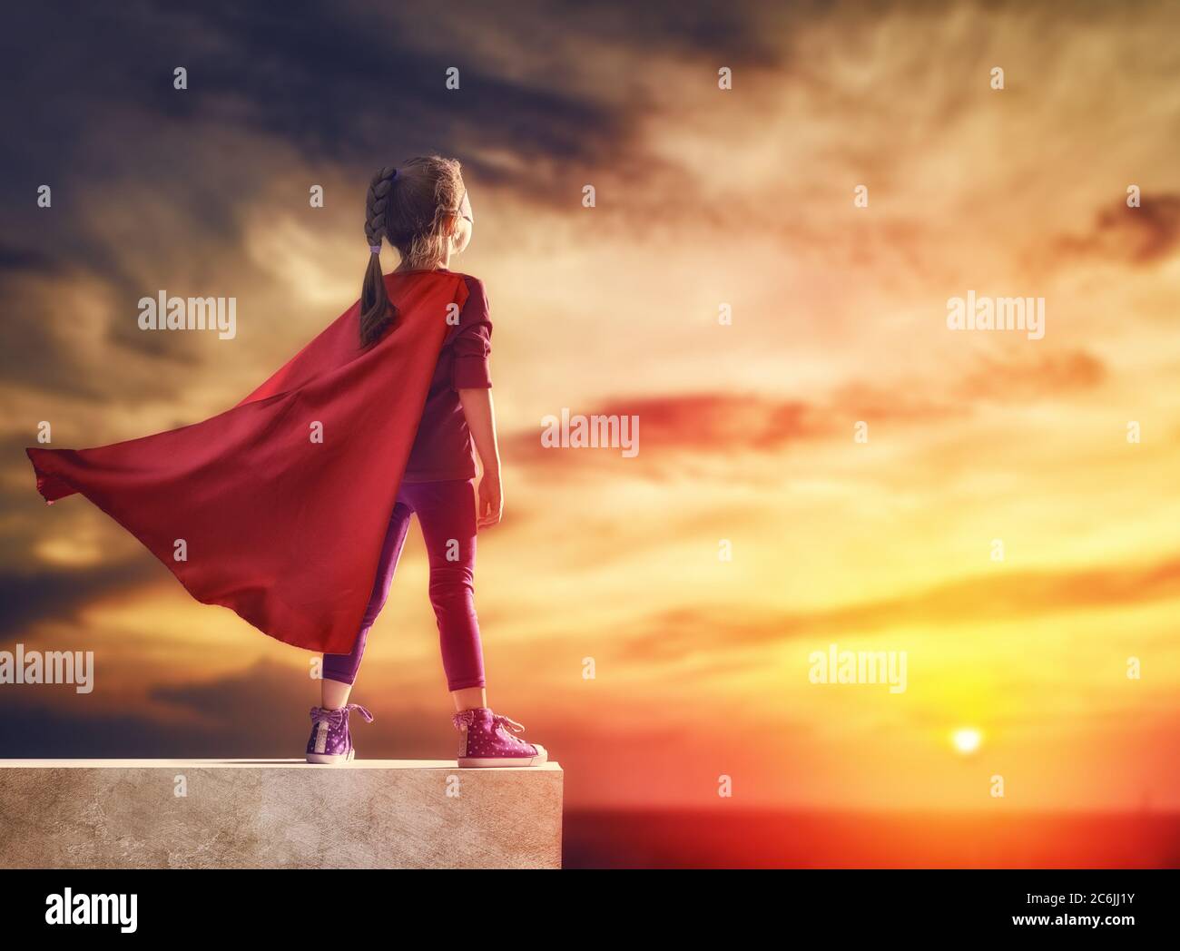 Little child plays superhero. Kid on the background of sunset sky. Girl ...