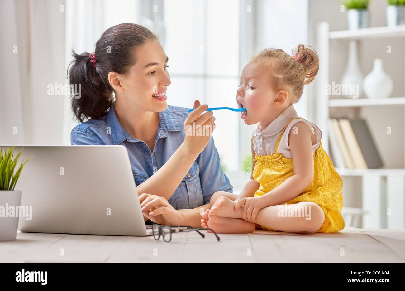 Young mother with toddler child working on the computer from home Stock ...