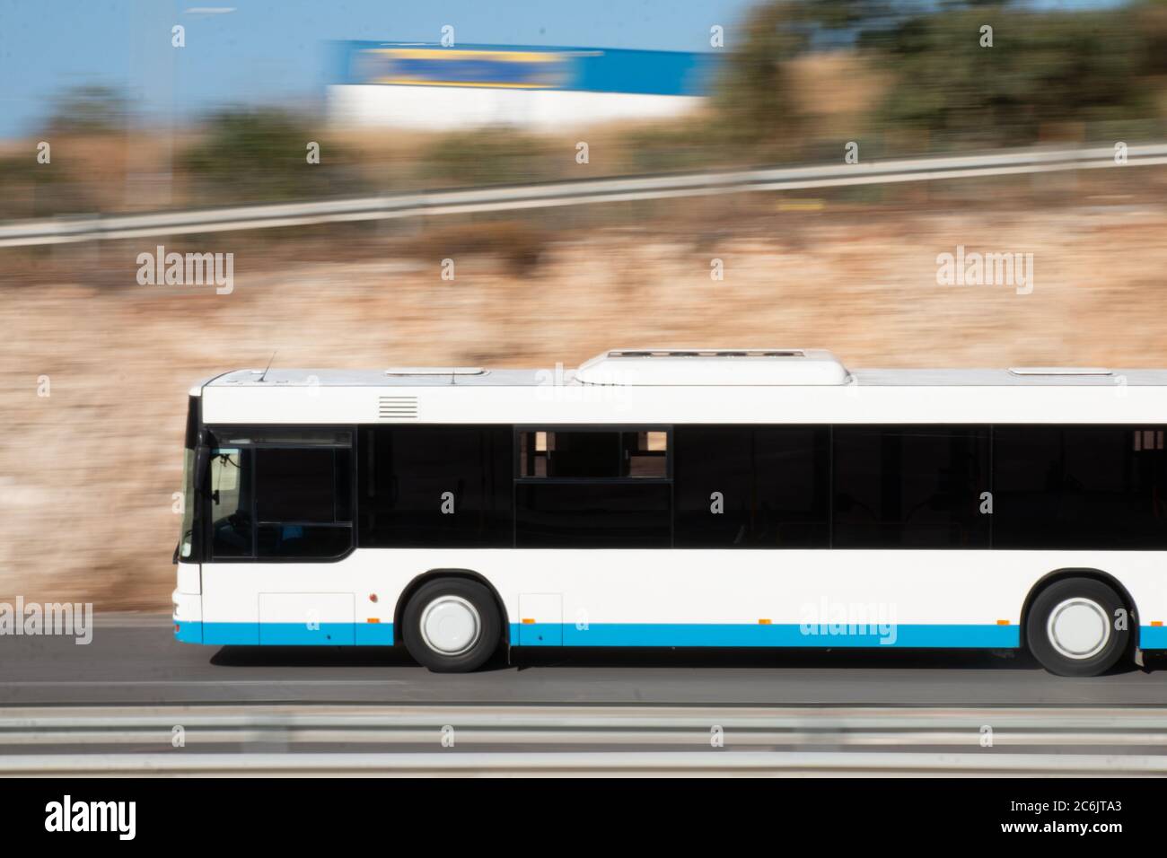 White bus moving fast along the street on a motion blurred background ...