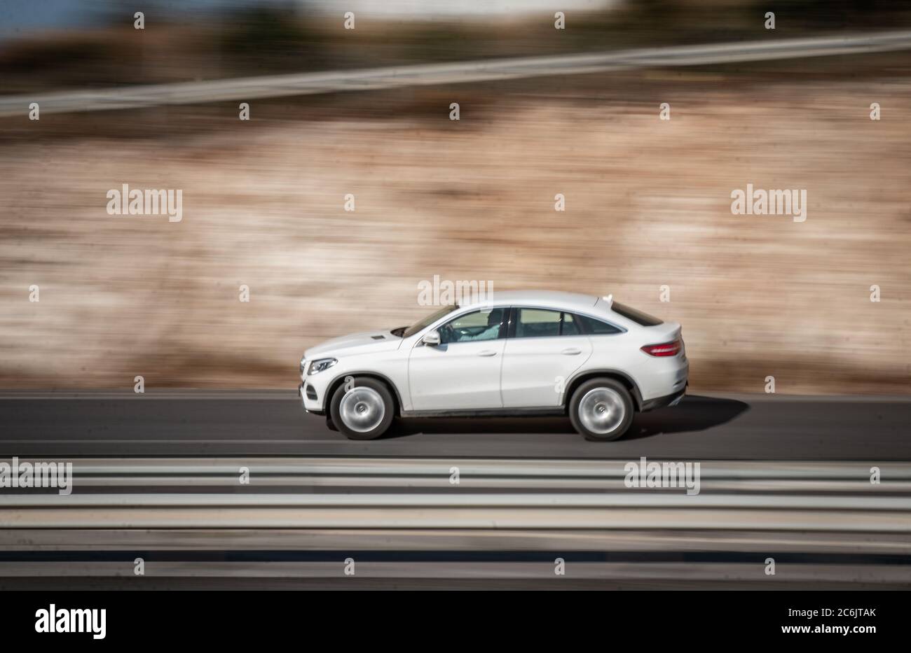 White car moving fast along the street on a motion blurred background ...