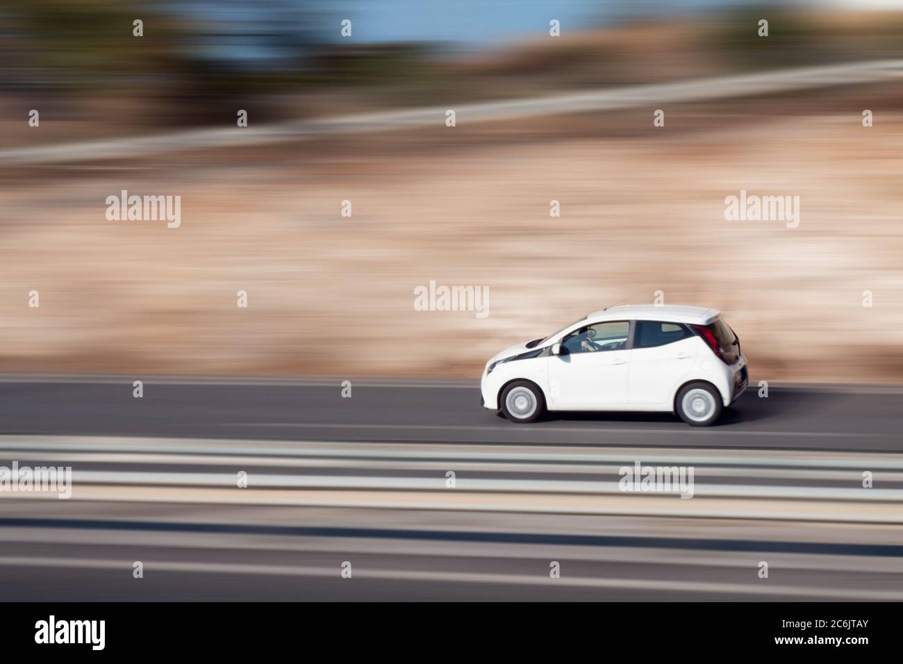 White car moving fast along the street on a motion blurred background ...
