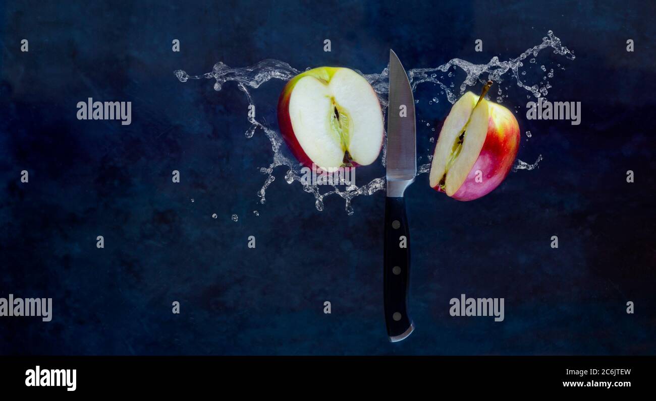 The sliced Red apple and A kitchen knife are floating in the air with ...