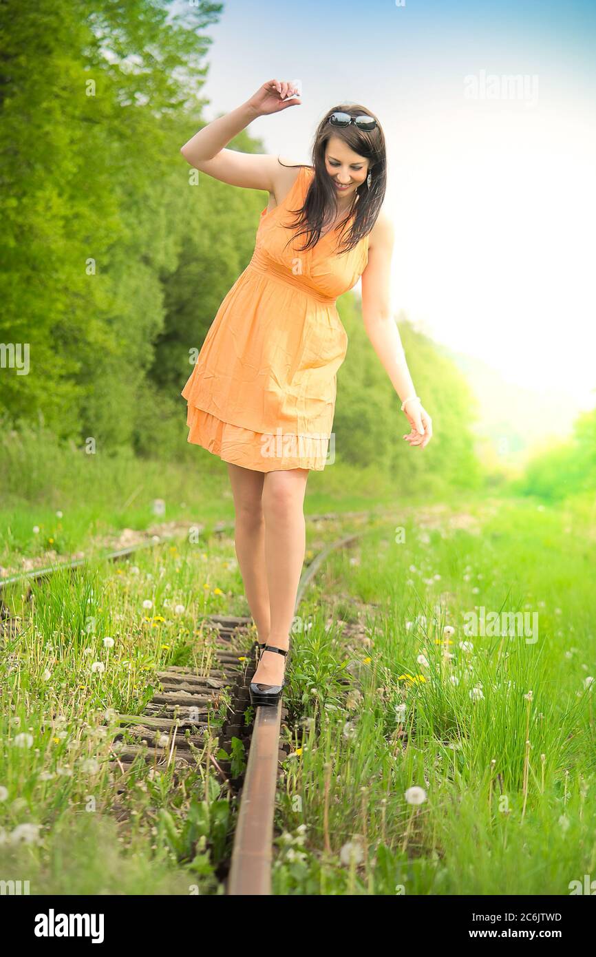 Pretty, happy woman walking on train tracks Stock Photo - Alamy