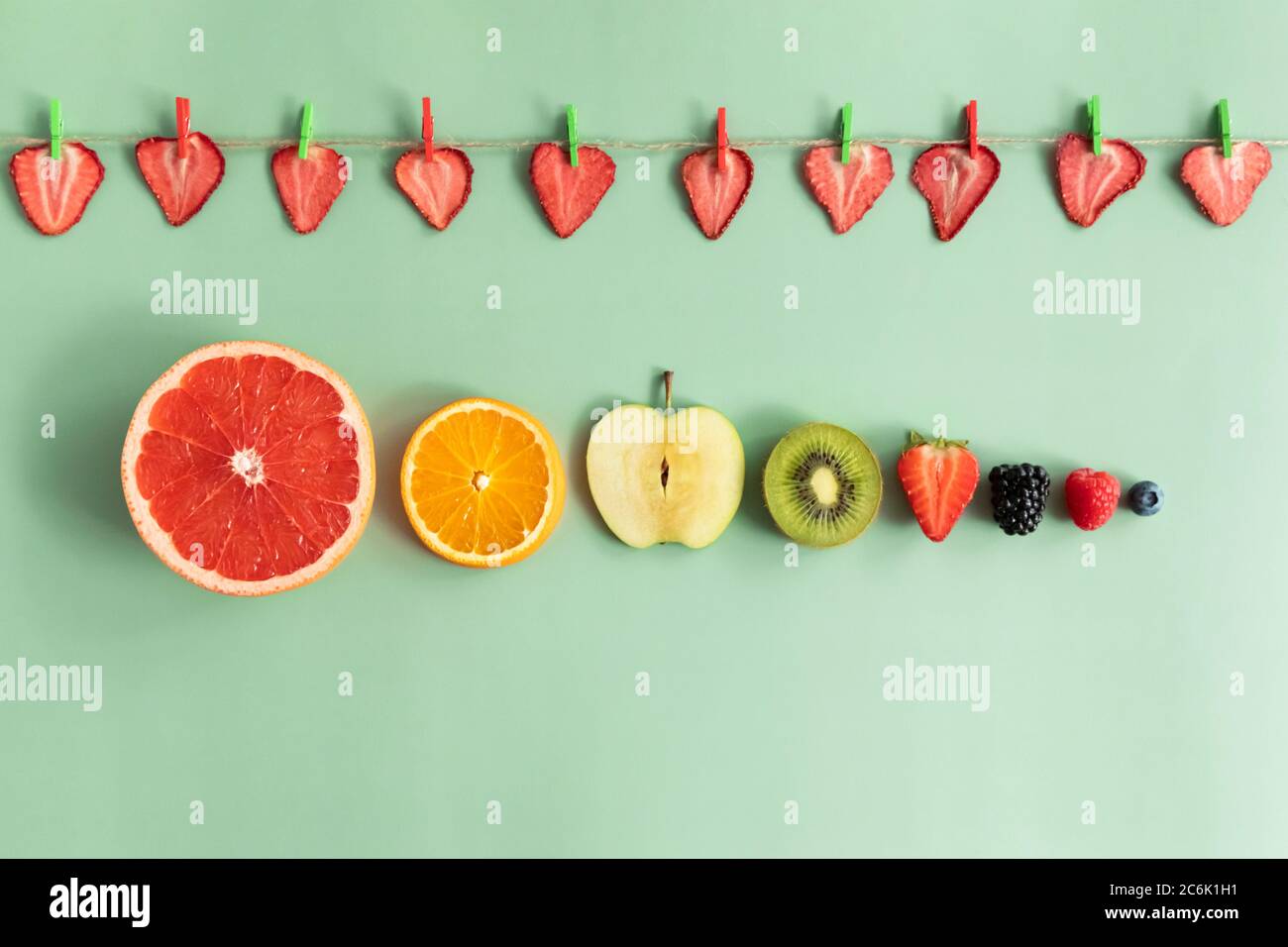 Slices of fruits and berries are located on a green background from ...